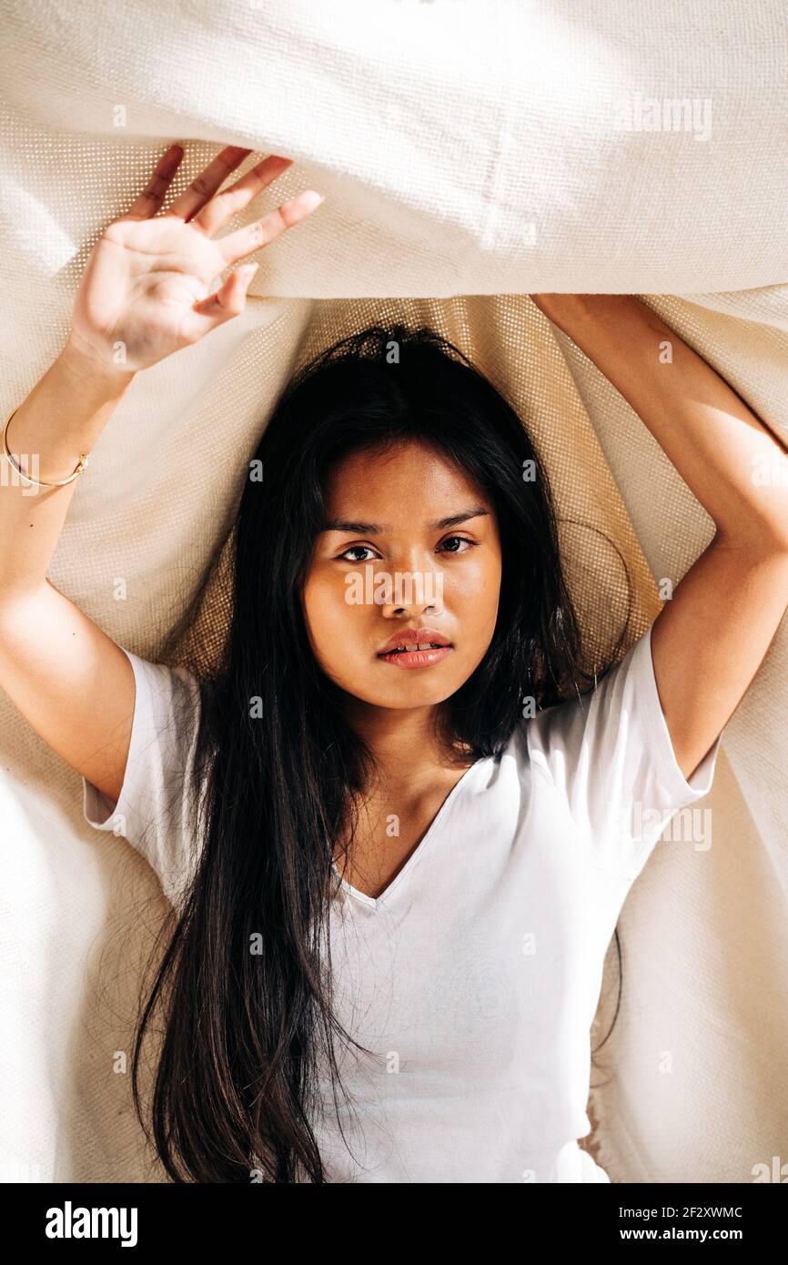 Attractive young Hispanic Woman wearing white t shirt touching blanket ...