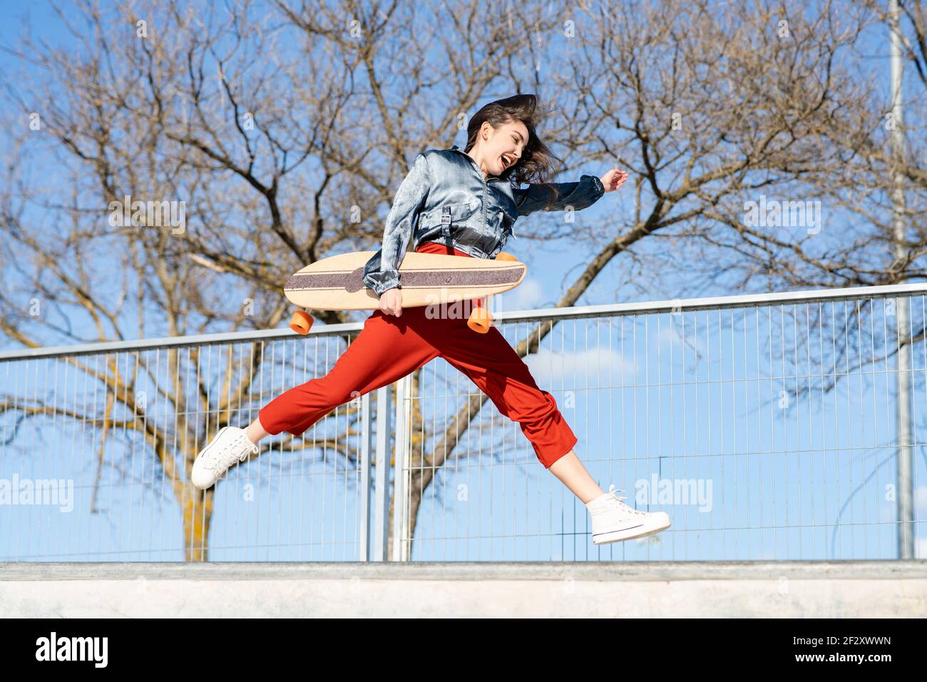 From below side view of happy young female in stylish apparel jumping ...