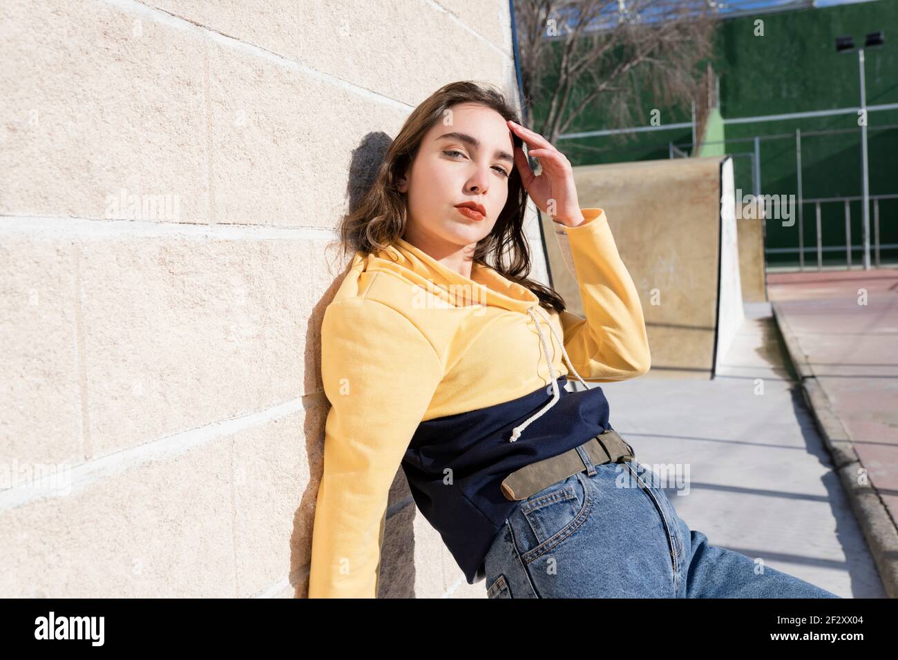 Side view of female teen with makeup in trendy wear touching forehead ...