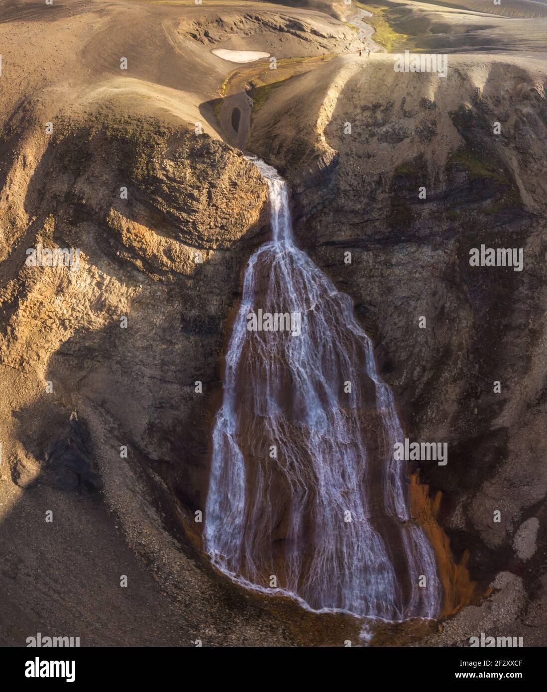 Rapid narrow stream flowing along rough rocky terrain and falling from ...