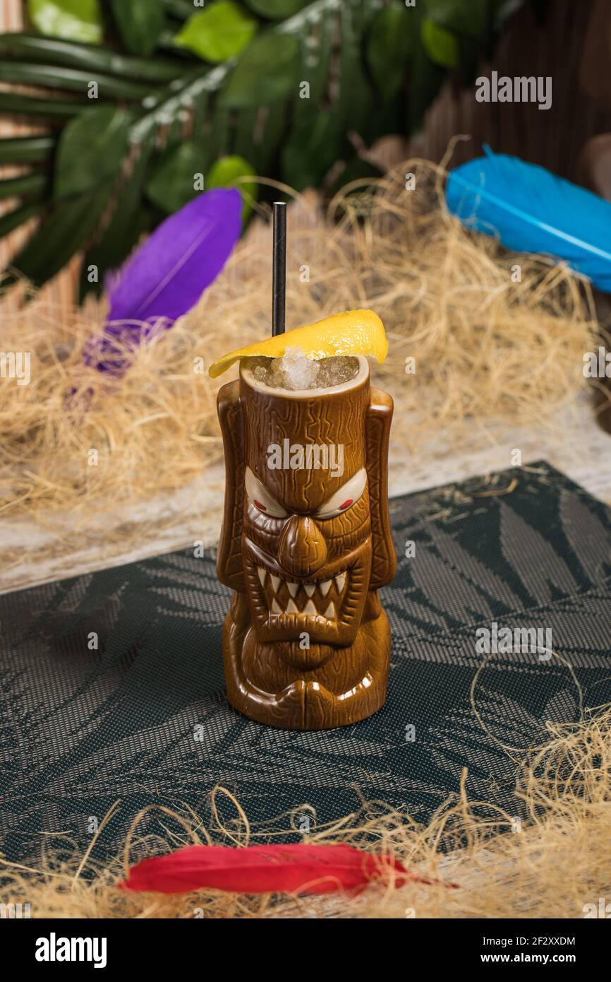 Brown sculptural tiki mug with alcohol drink decorated with straw and ...