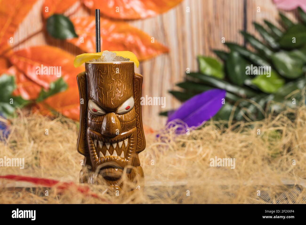 Brown sculptural tiki mug with alcohol drink decorated with straw and ...