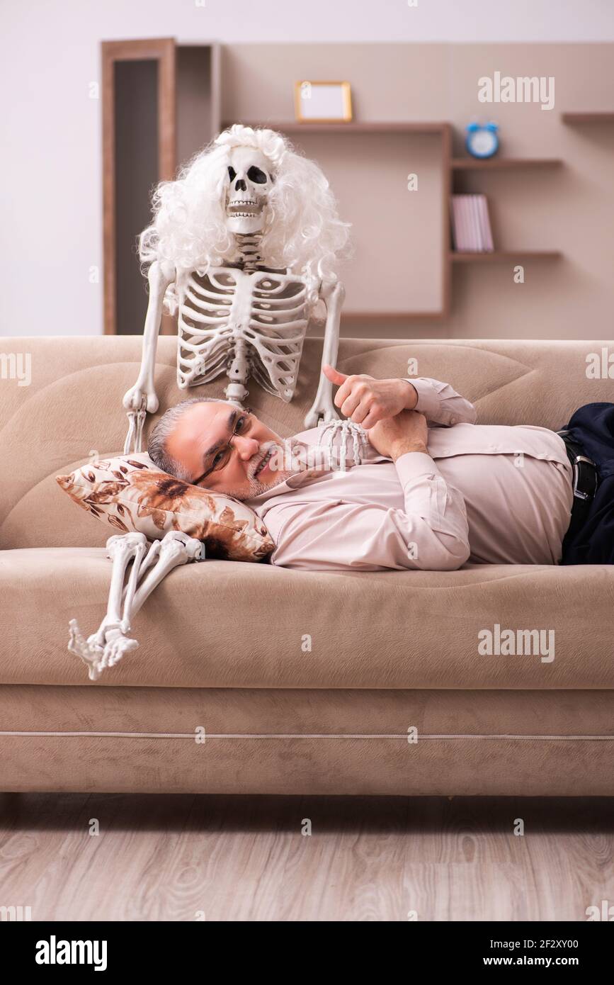 Old man sitting on the sofa with the female skeleton in undying love ...