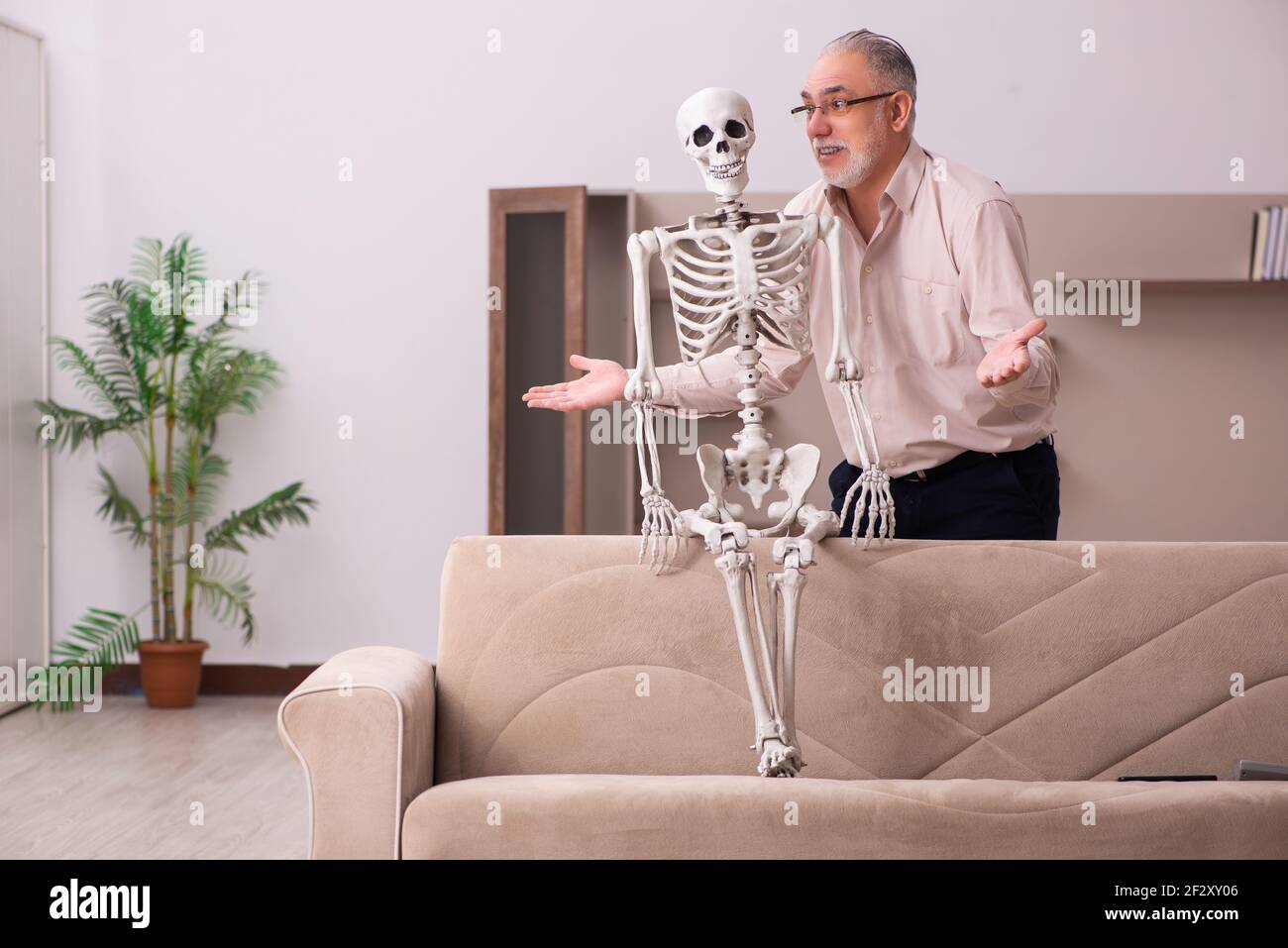 Old man sitting on the sofa with the female skeleton in undying love ...