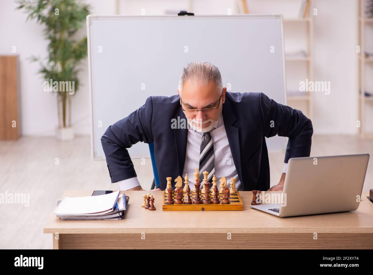 Old businessman employee playing chess at workplace Stock Photo - Alamy
