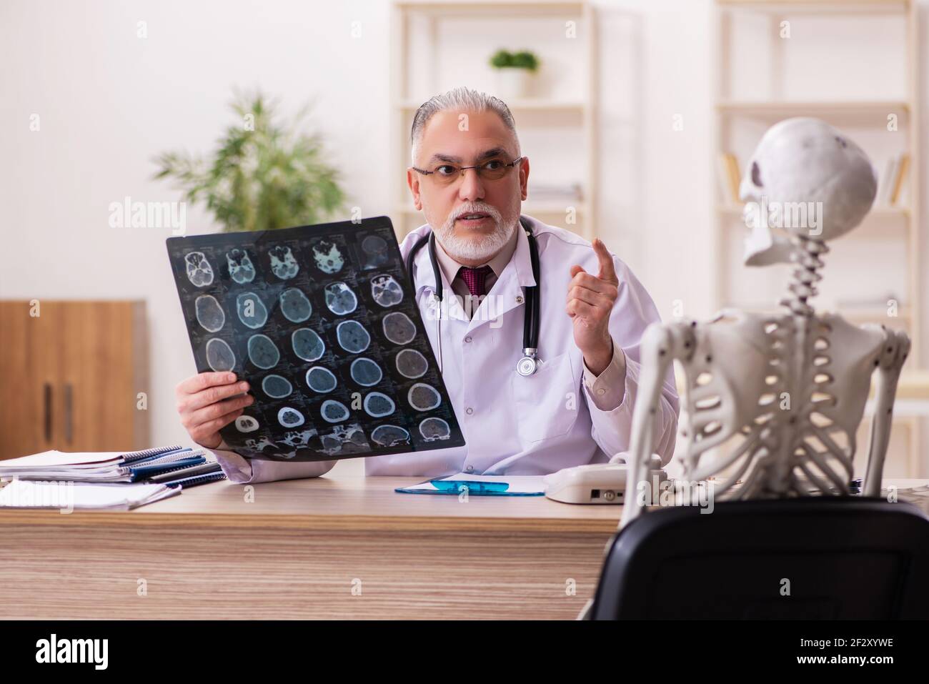 Skeleton patient visiting old male doctor radiologist Stock Photo - Alamy