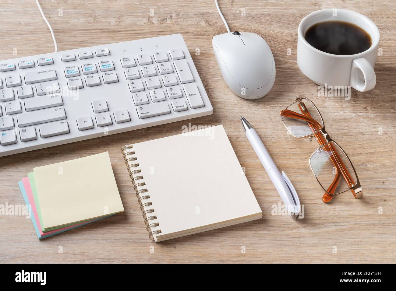 PC keyboard, mouse, paper notepad, glasses and cup of coffe on a desk ...