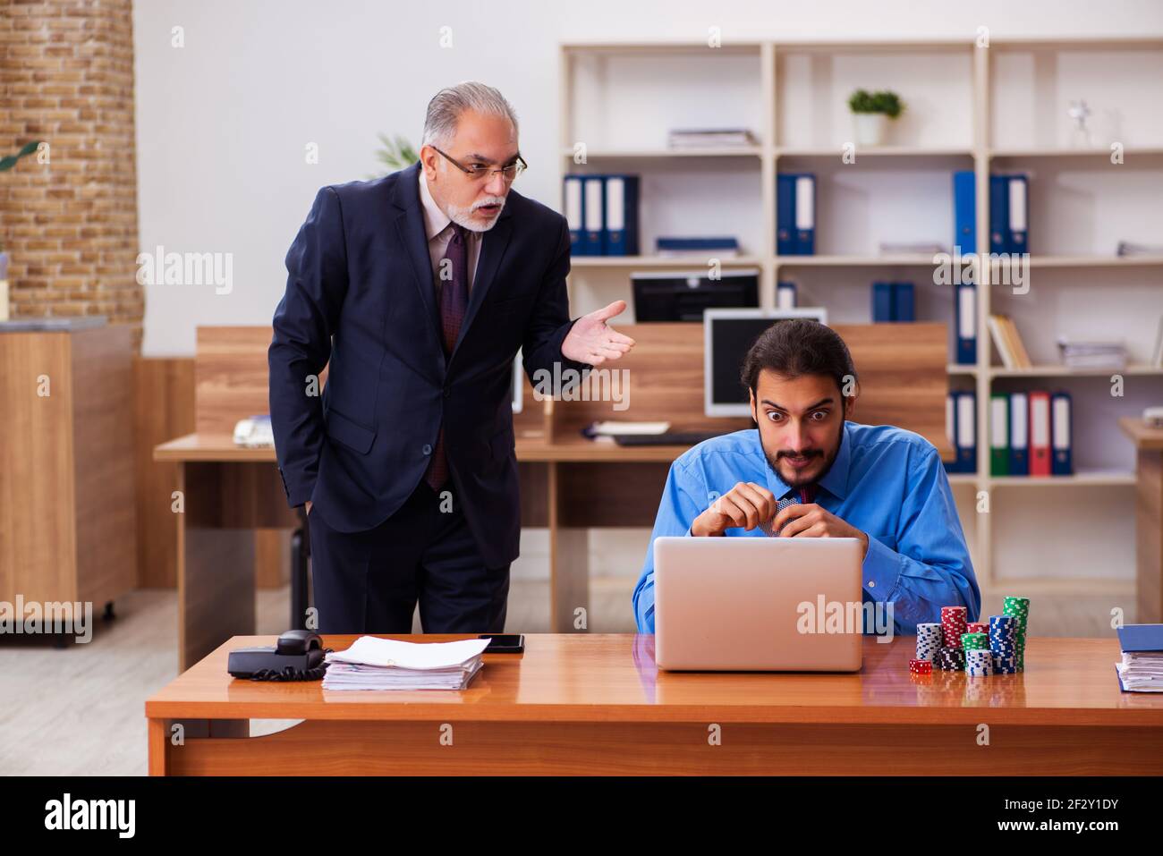 Two male employees in gambling concept in the office Stock Photo - Alamy