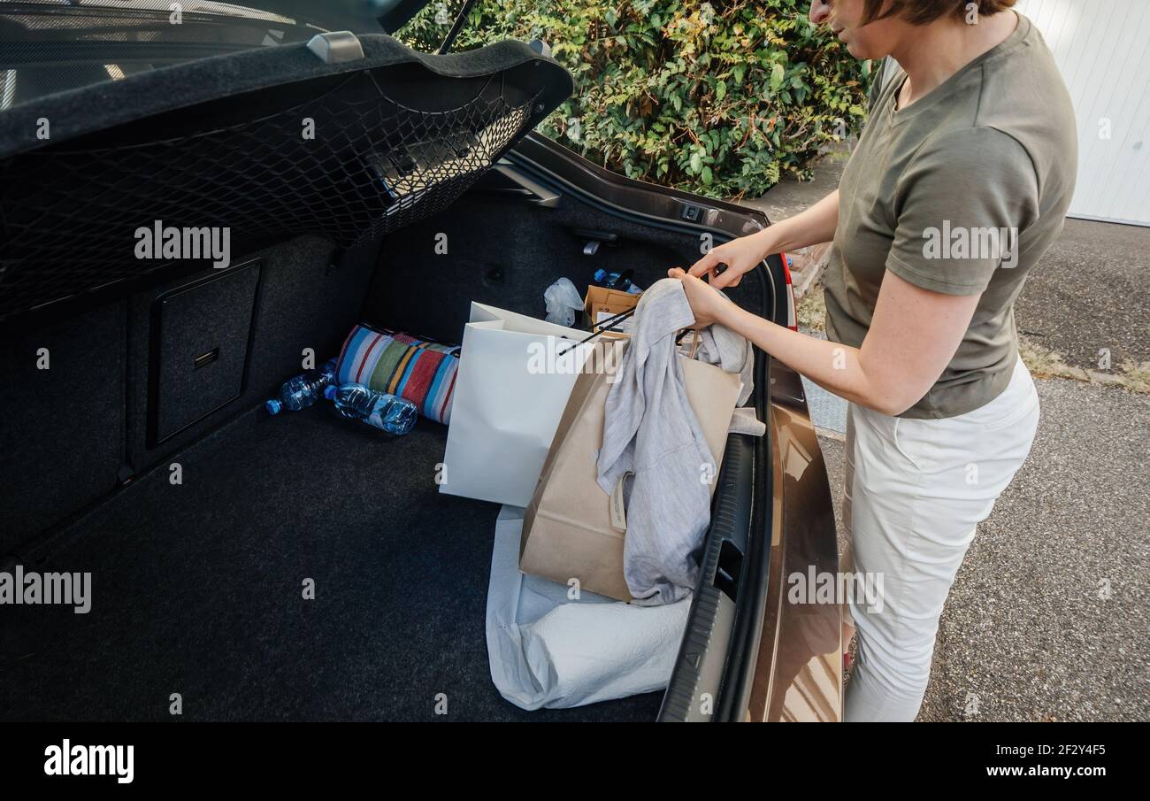 Overhead view of Young woman unloading car trunk with multiple bags ...
