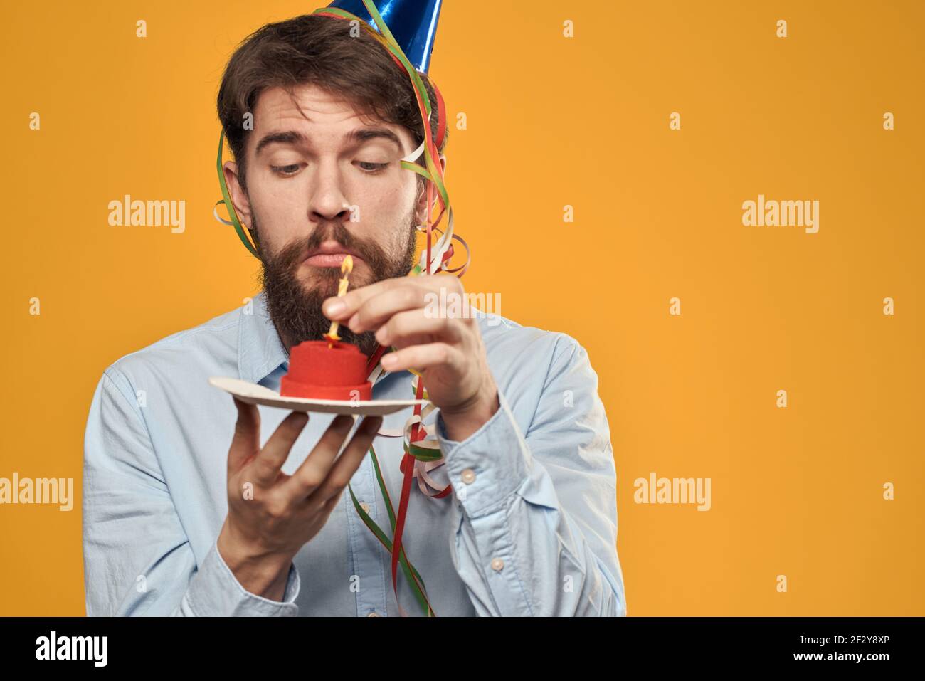 Guy with a cake in a plate on a yellow background holidays candle ...