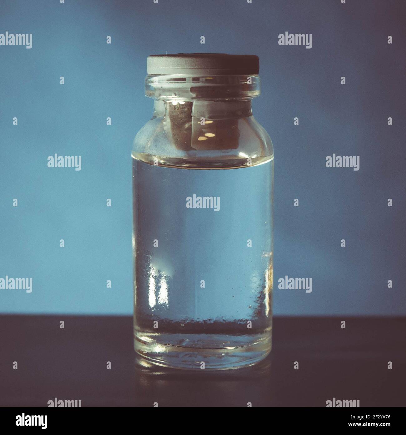 Vaccine in vitro. Medicine in a flask on a blue background. Antibiotic ...