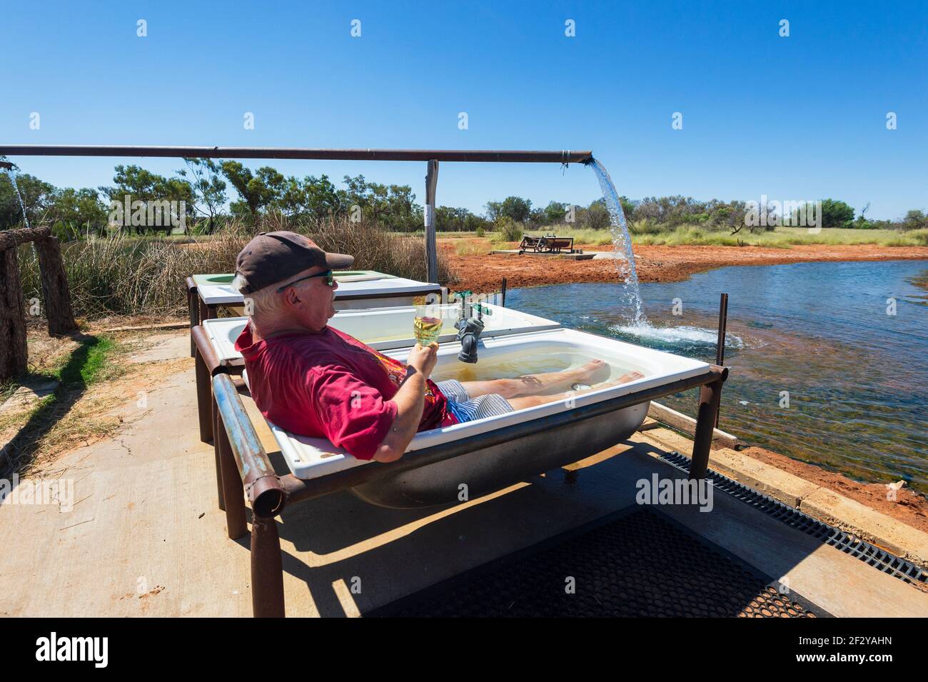 Tourist relaxing with a glass of wine in the Hot Bore Baths at ...