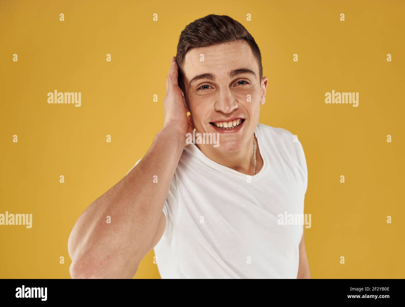 An energetic guy in a white T-shirt touches his head with his hand on a ...