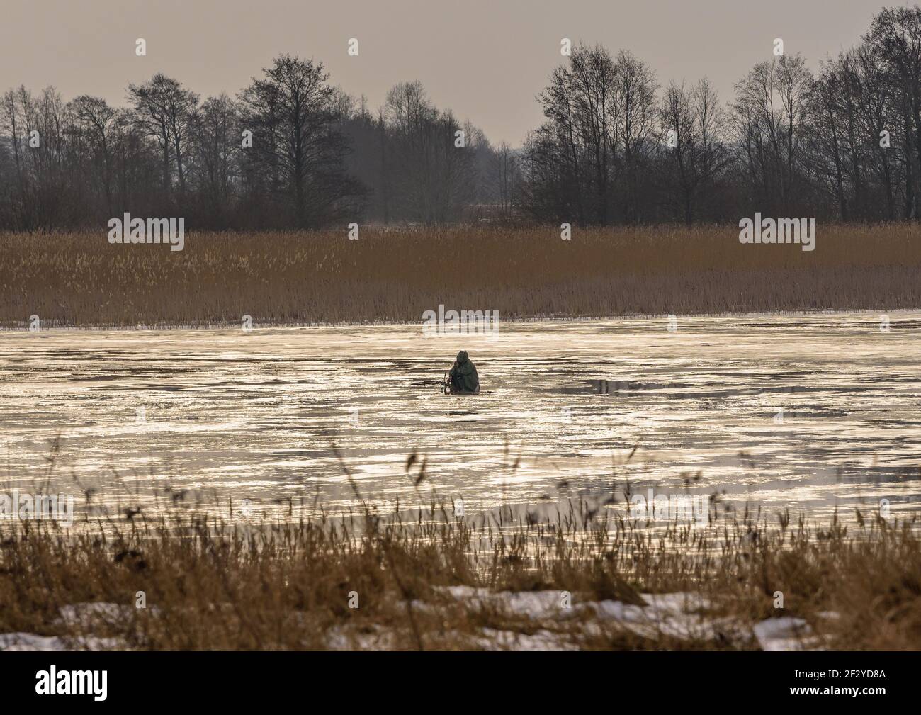 frozen river, bent and icy anglers fishing or moving along a frozen ...