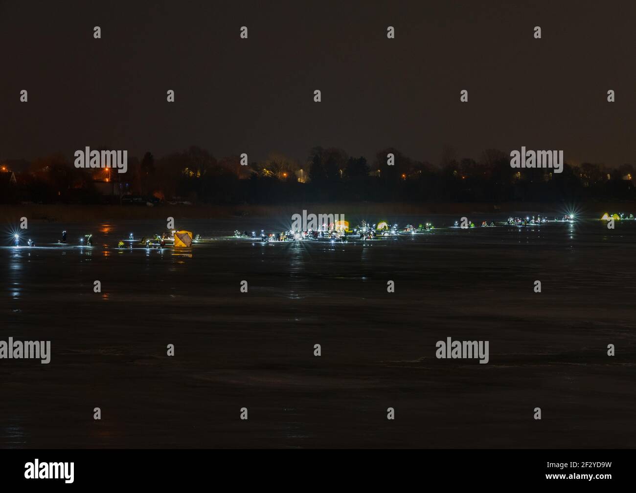 frozen river, night and ice anglers fish in the dark with artificial ...