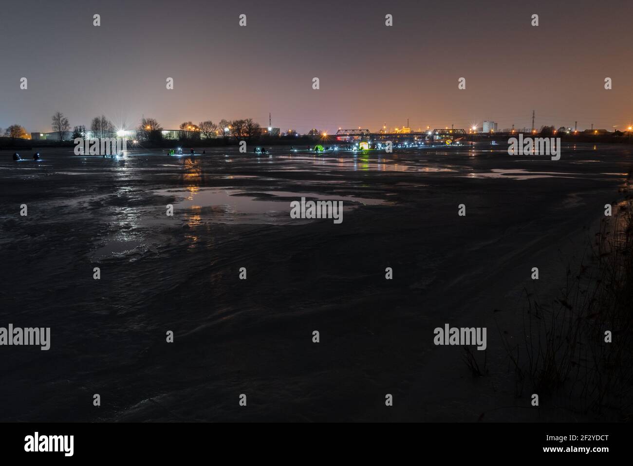 frozen river, night and ice anglers fish in the dark with artificial ...