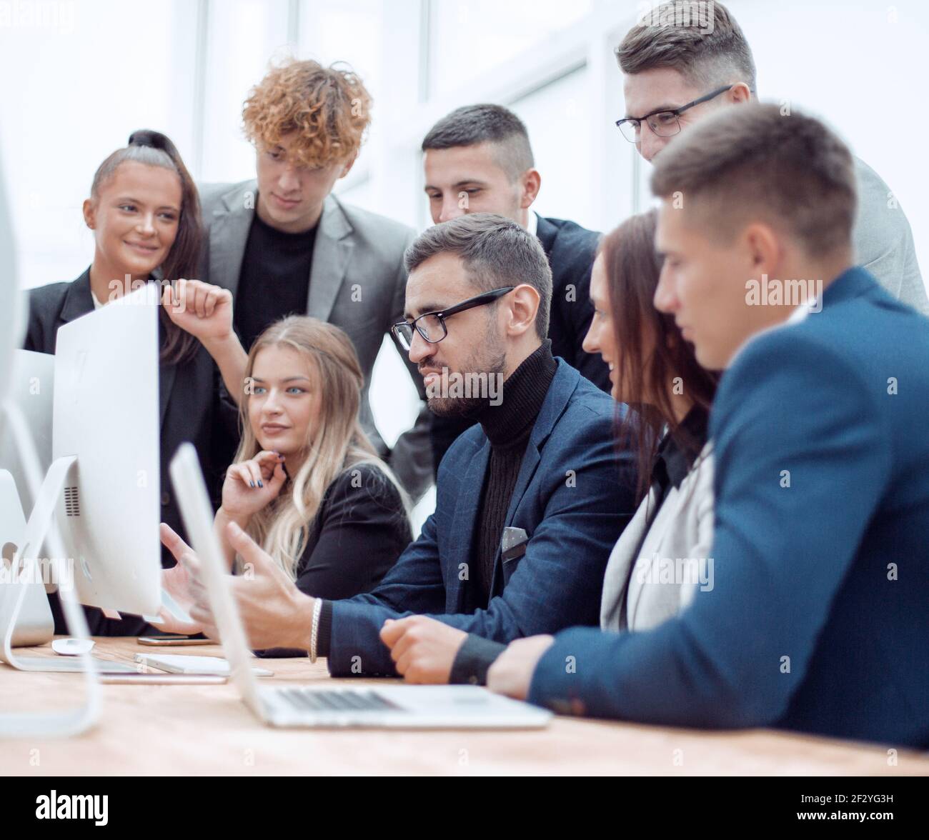 team of young employees looking together at a computer screen Stock ...