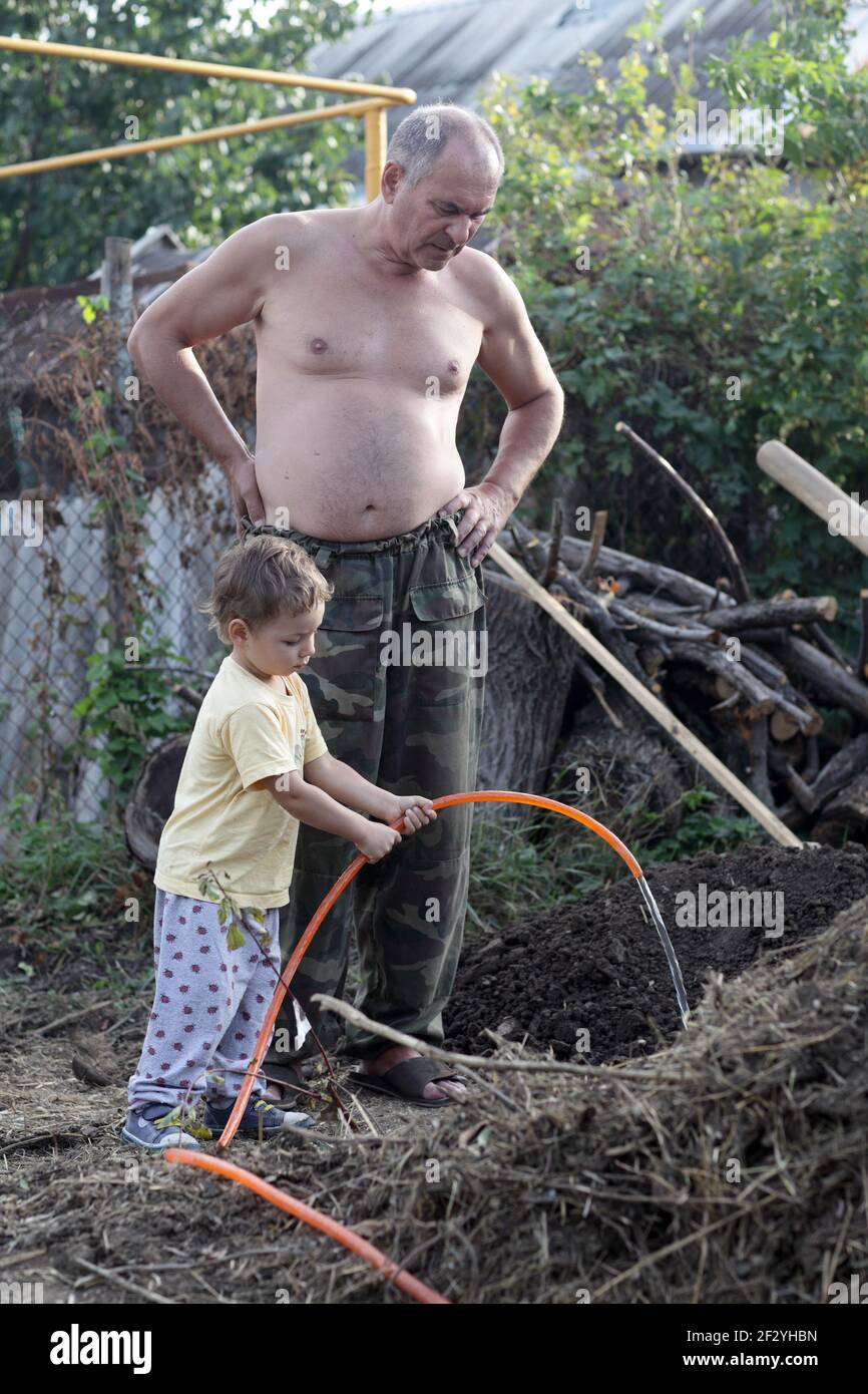 Grandson and grandfather watering plant hi-res stock photography and ...