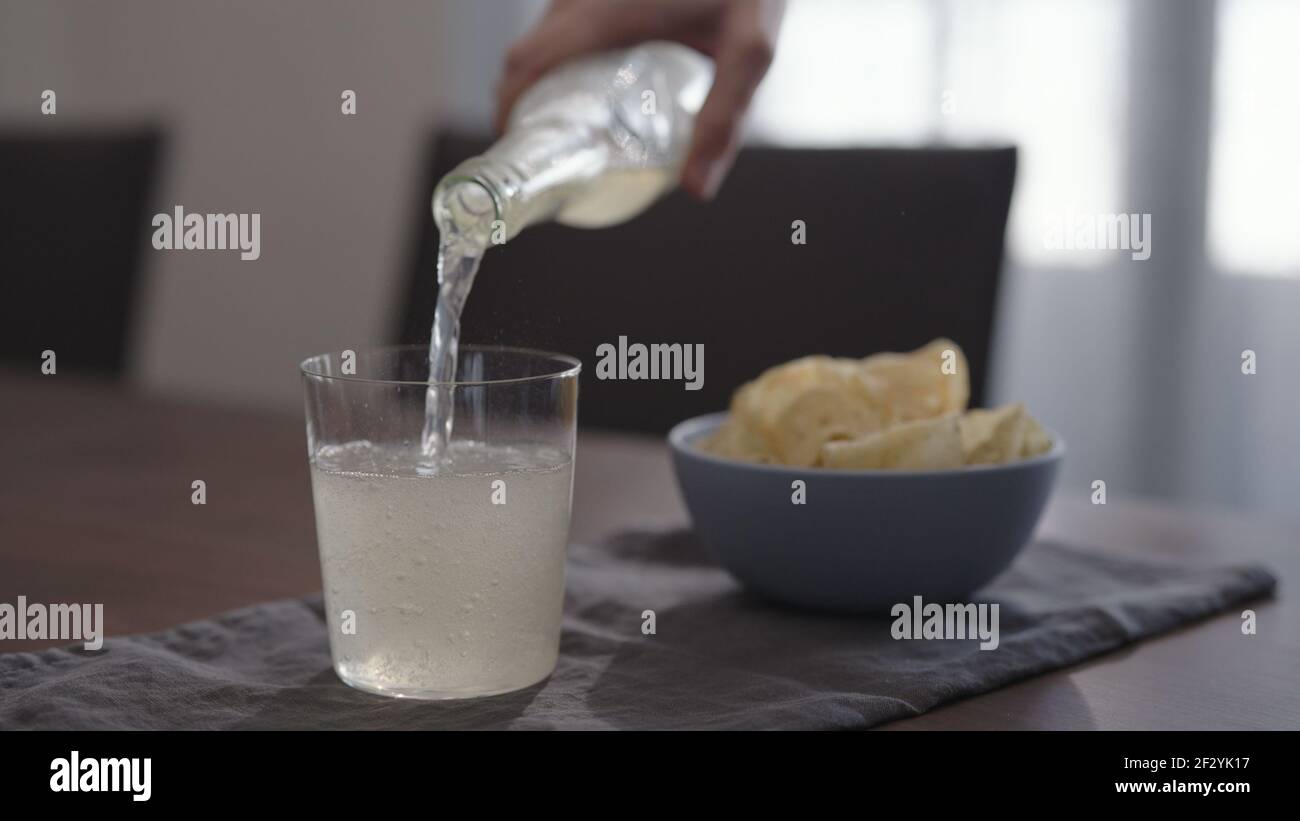 man pour ginger beer into tumbler glass with blue bowl full of potato ...
