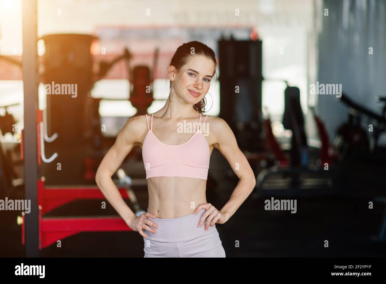 Athletic girl in sportswear performs exercises with a barbell ...
