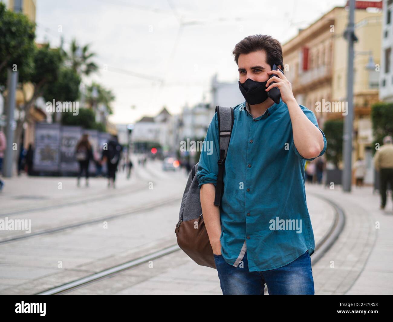 A Spanish male with face mask talking on the phone outdoors - concept ...