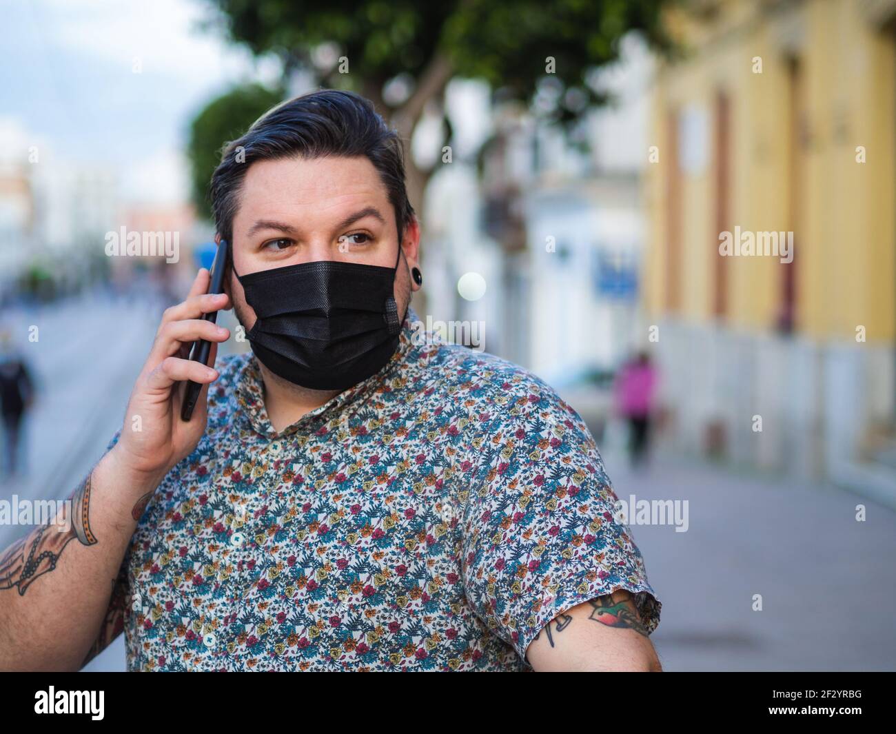 A Spanish male with face mask talking on the phone outdoors - concept ...