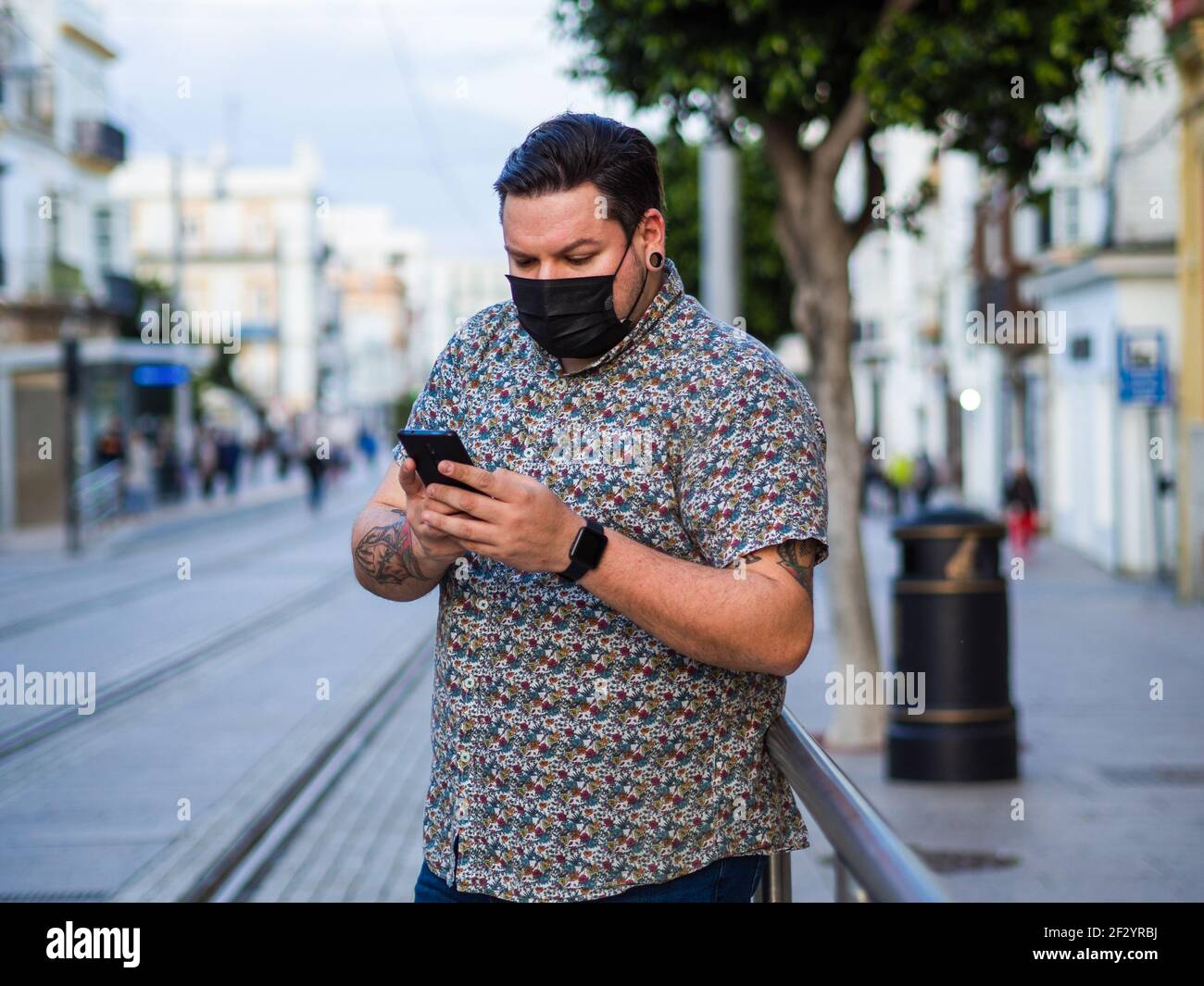 A Spanish male with face mask using phone outdoors - concept of the new ...