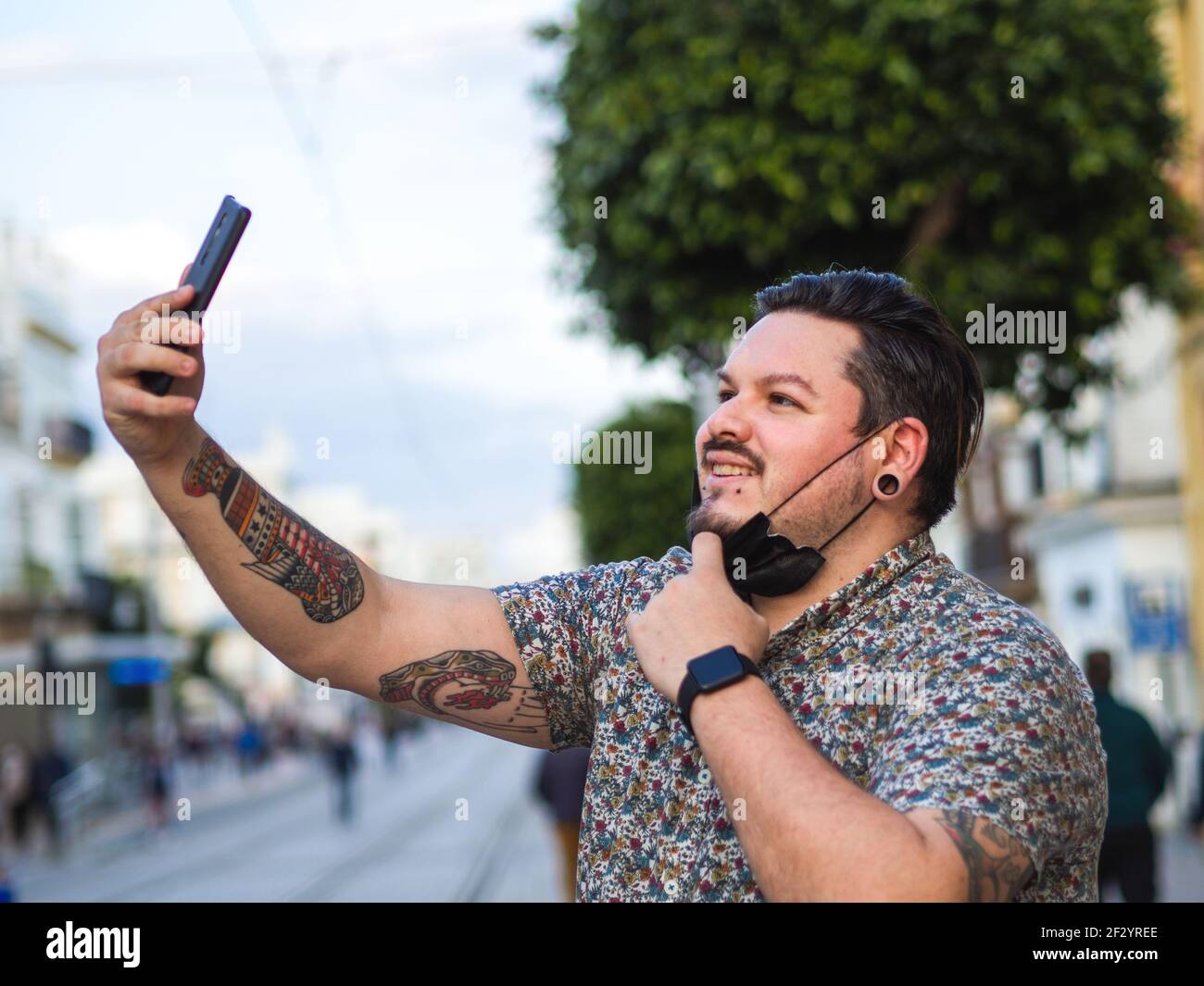 A Spanish male with face mask taking a selfie outdoors - concept of the ...