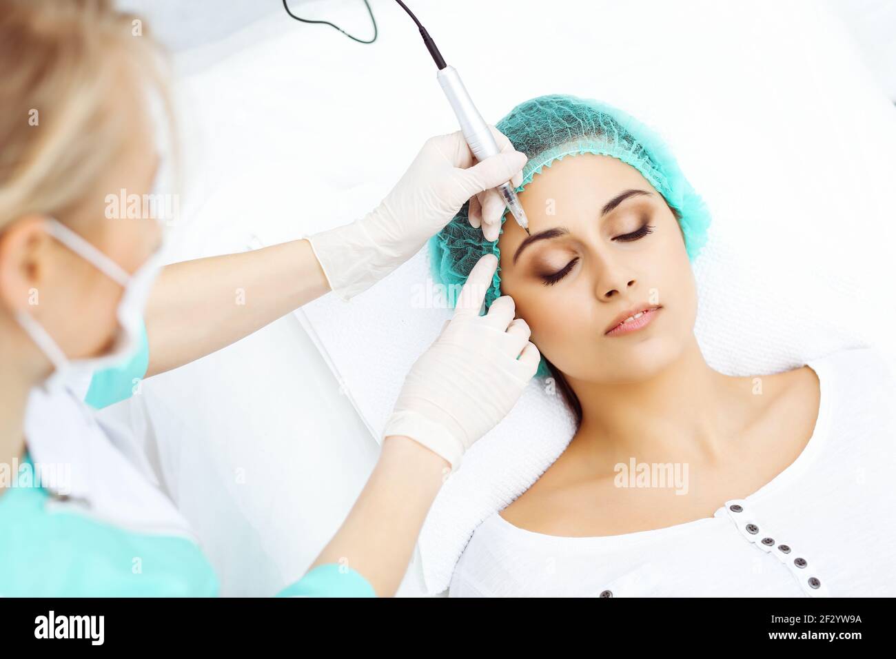 Professional beautician doing eyebrow tattoo at woman face. Permanent ...