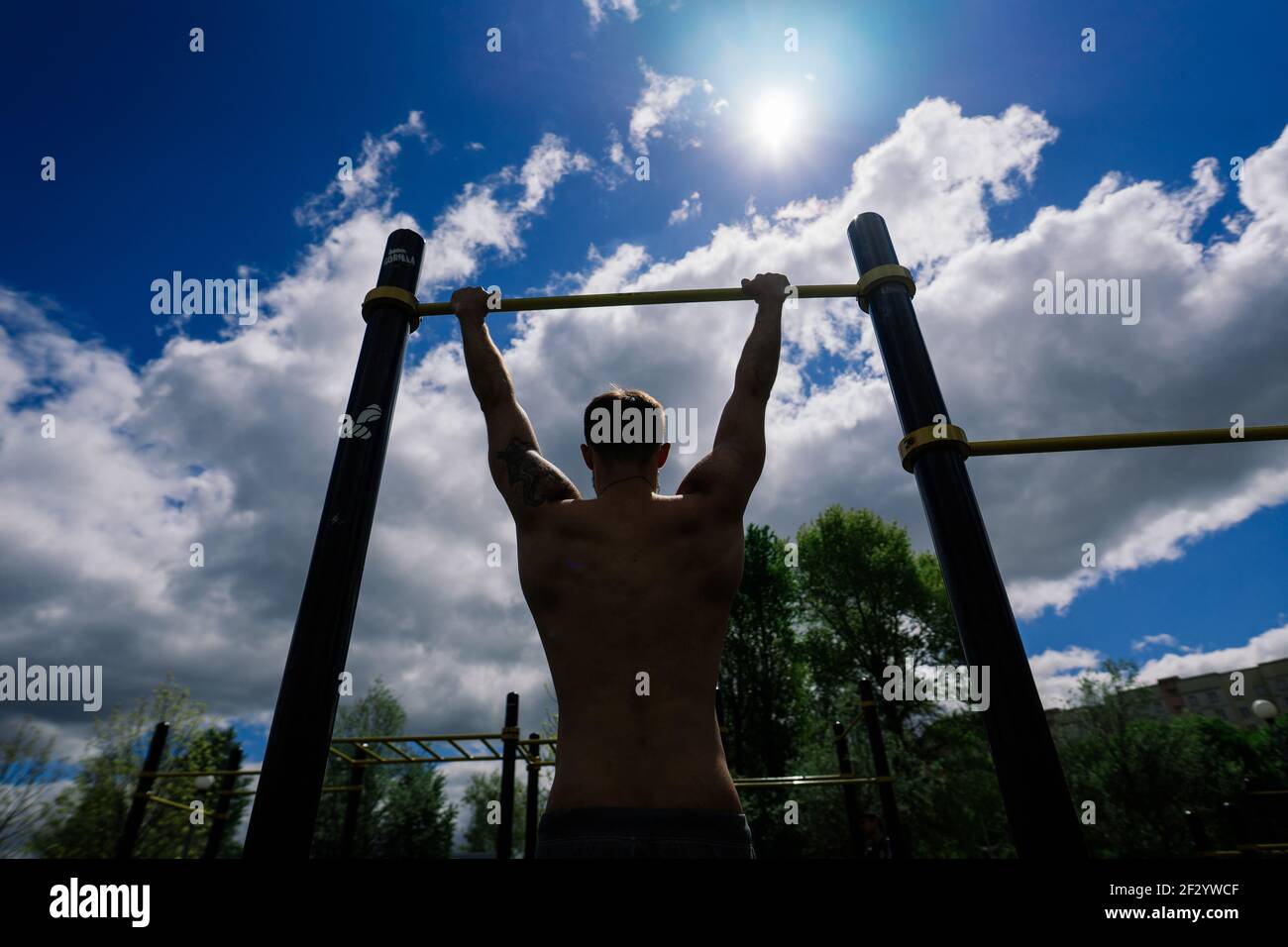 Caucasian sportsman pulling up wide grip hand on crossbar during street ...