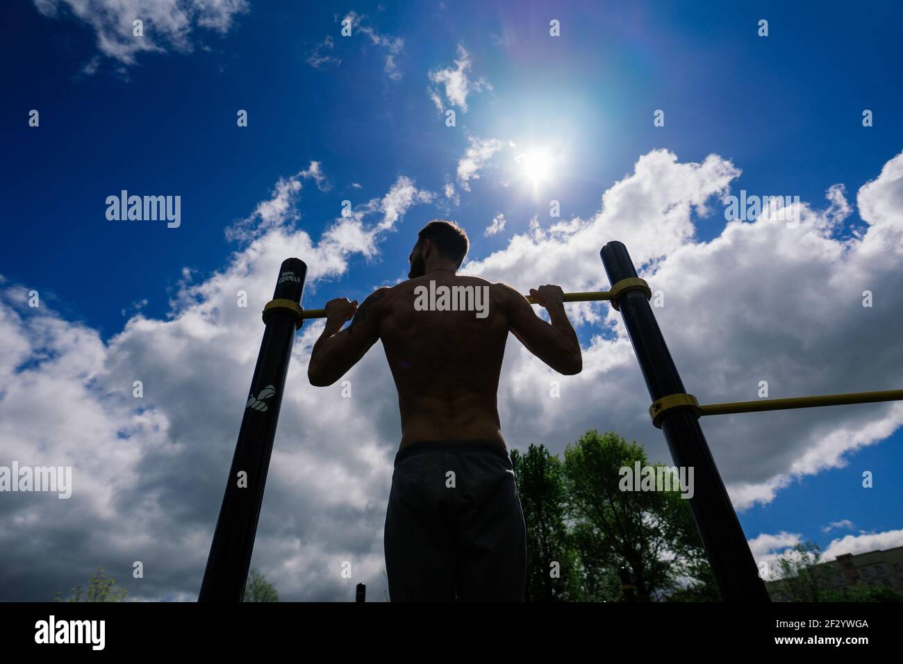 Caucasian sportsman pulling up wide grip hand on crossbar during street ...