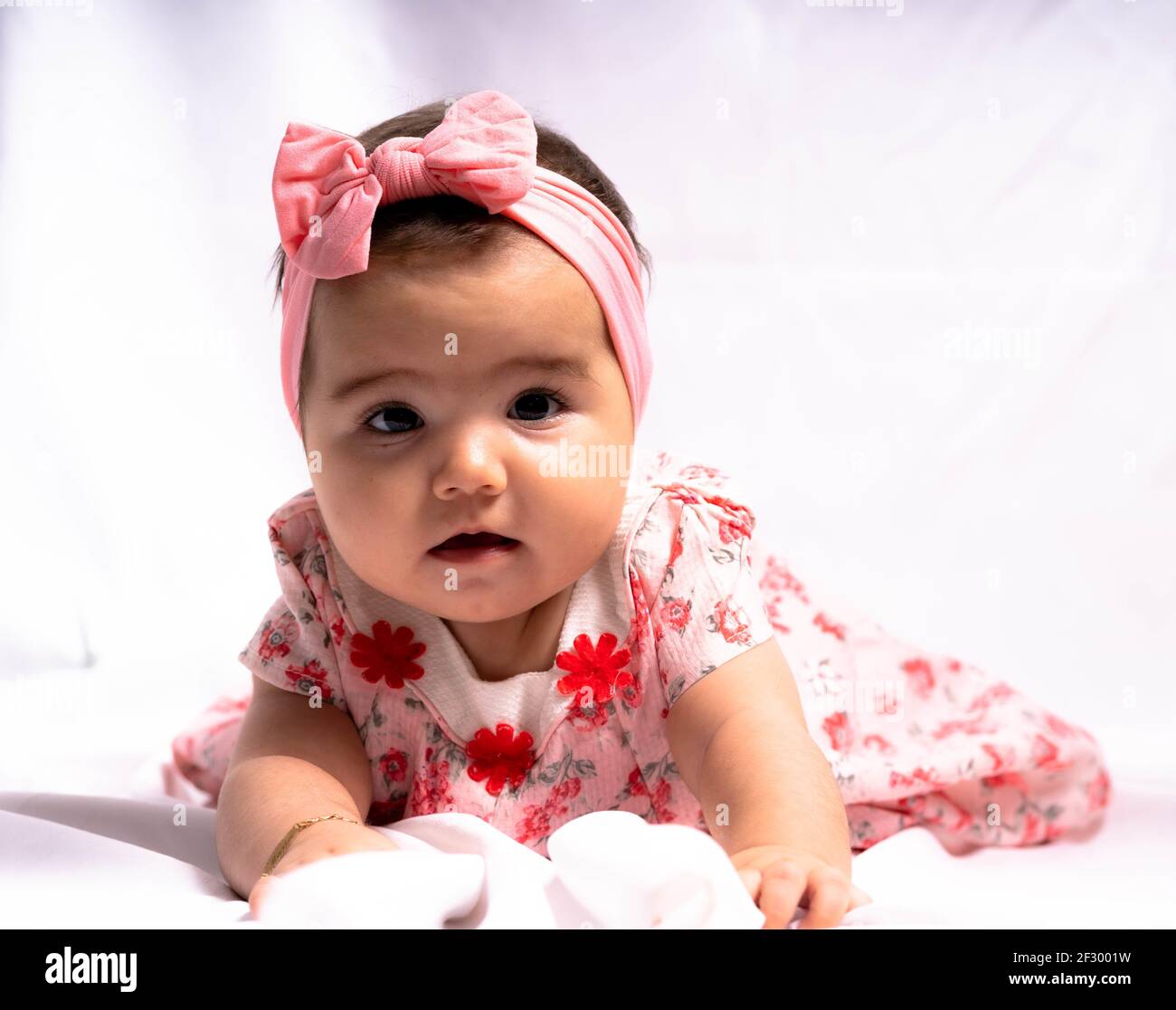 A Spanish kid with pink dress and headband on white background Stock ...