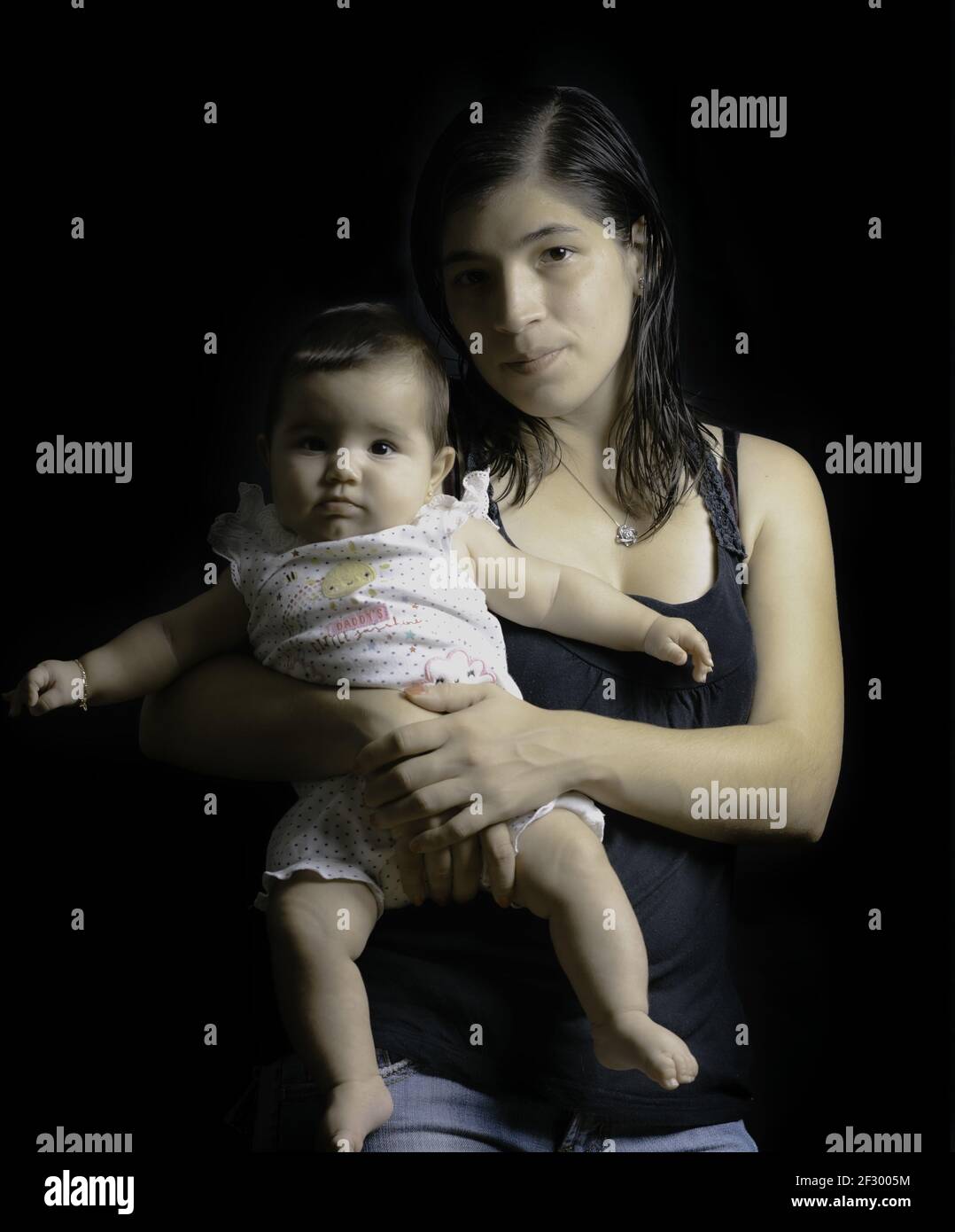 A vertical shot of a Spanish mother with her baby on black background ...