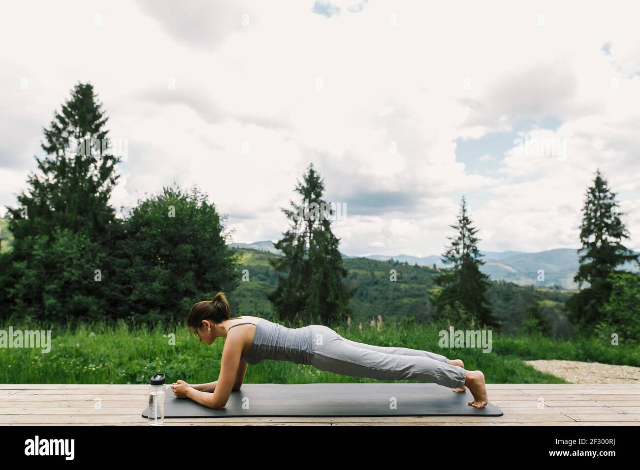 Young fit woman doing plank on yoga mat on background of sunny ...