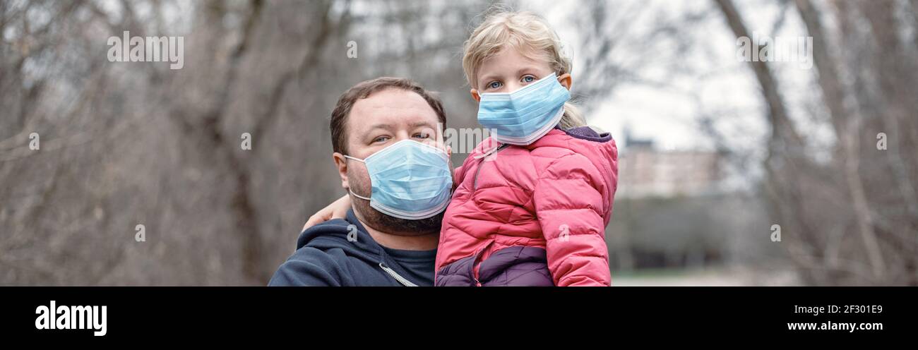 Father with child girl wearing sanitary face masks outdoor. Family dad ...