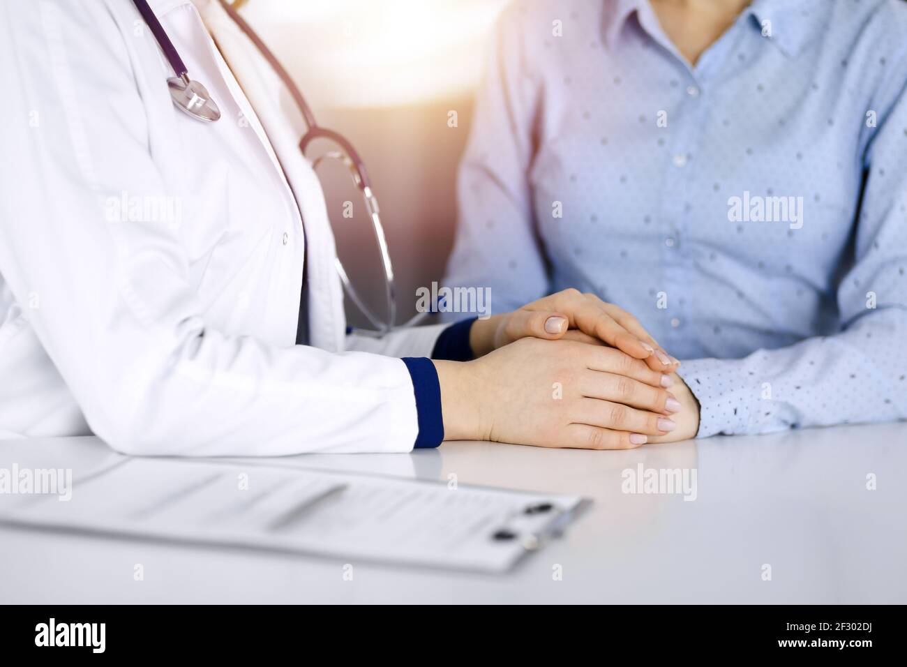 Unknown woman-doctor is holding her patient's hands to reassure a ...