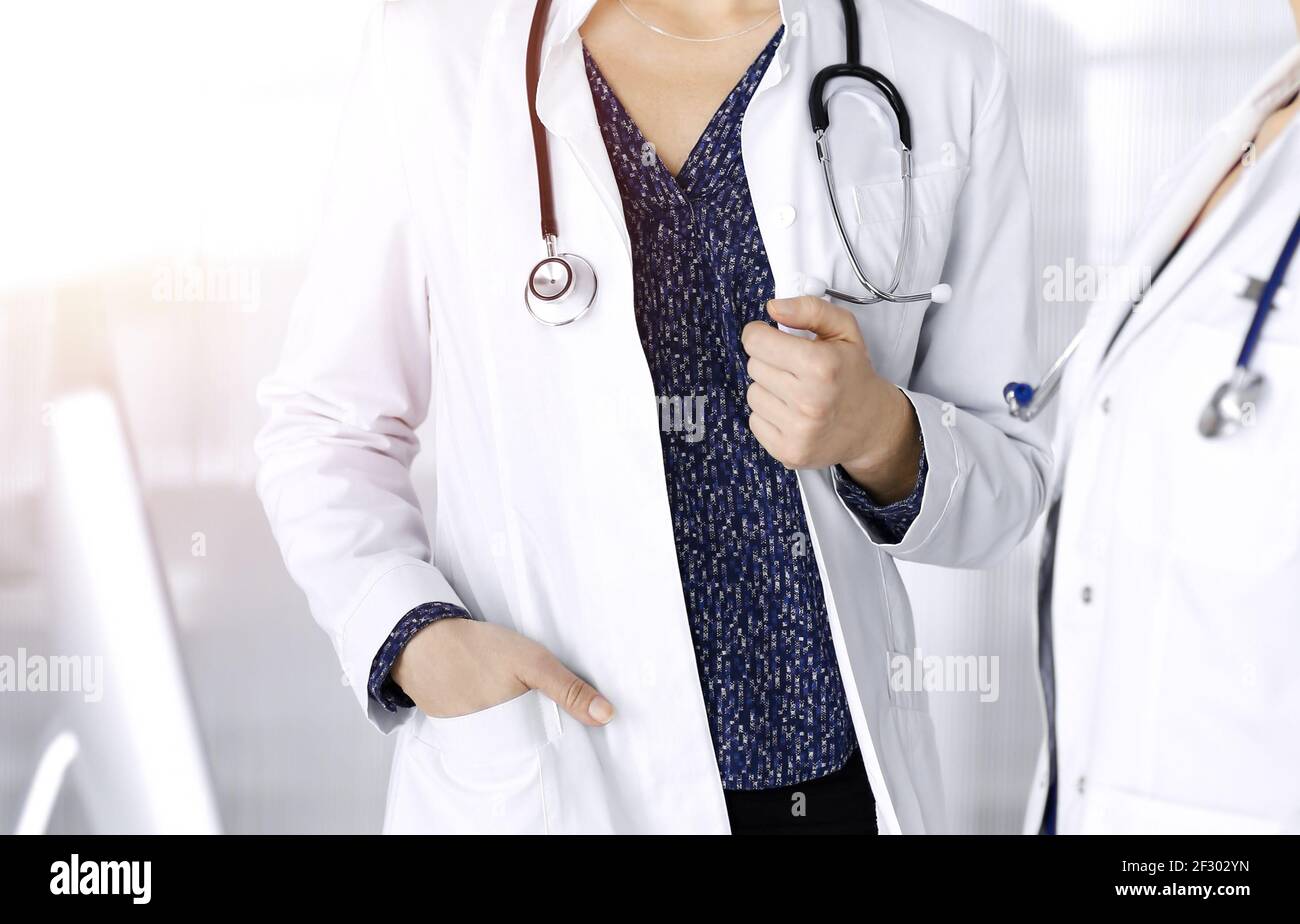 Two female physicians are discussing medical therapy, while standing at ...