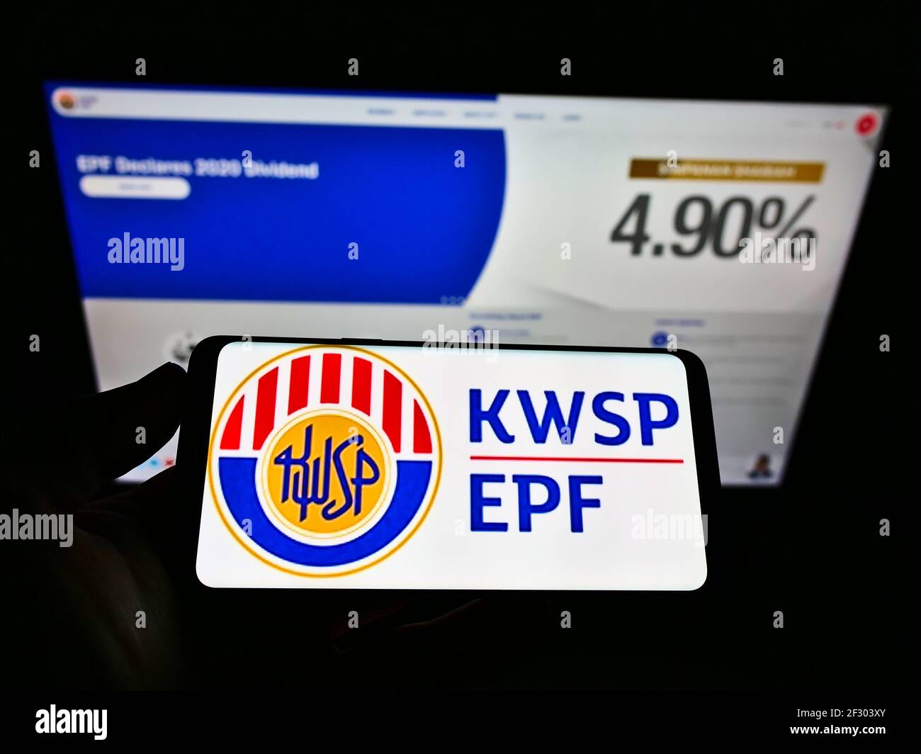 Person holding mobile phone with logo of Malaysian Employees Provident ...