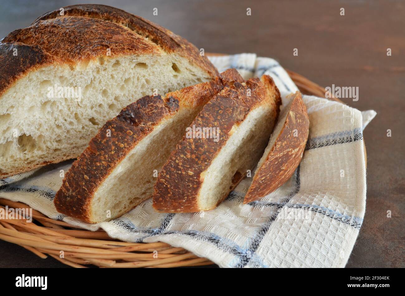 Close-up of sliced homemade bread with a crisp crust on a kitchen towel ...