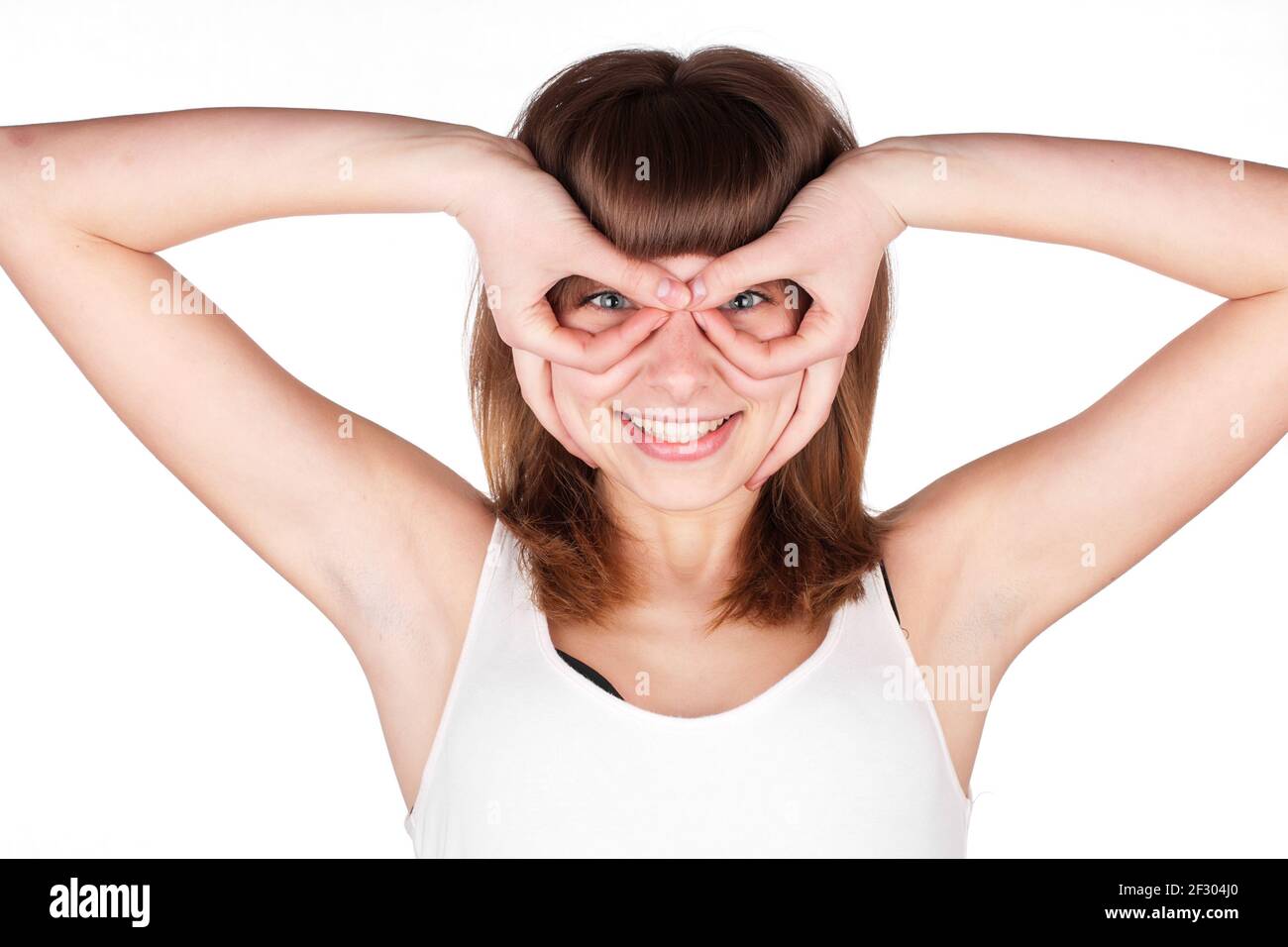 Young woman makes glasses with fingers. The girl looks in impromptu ...