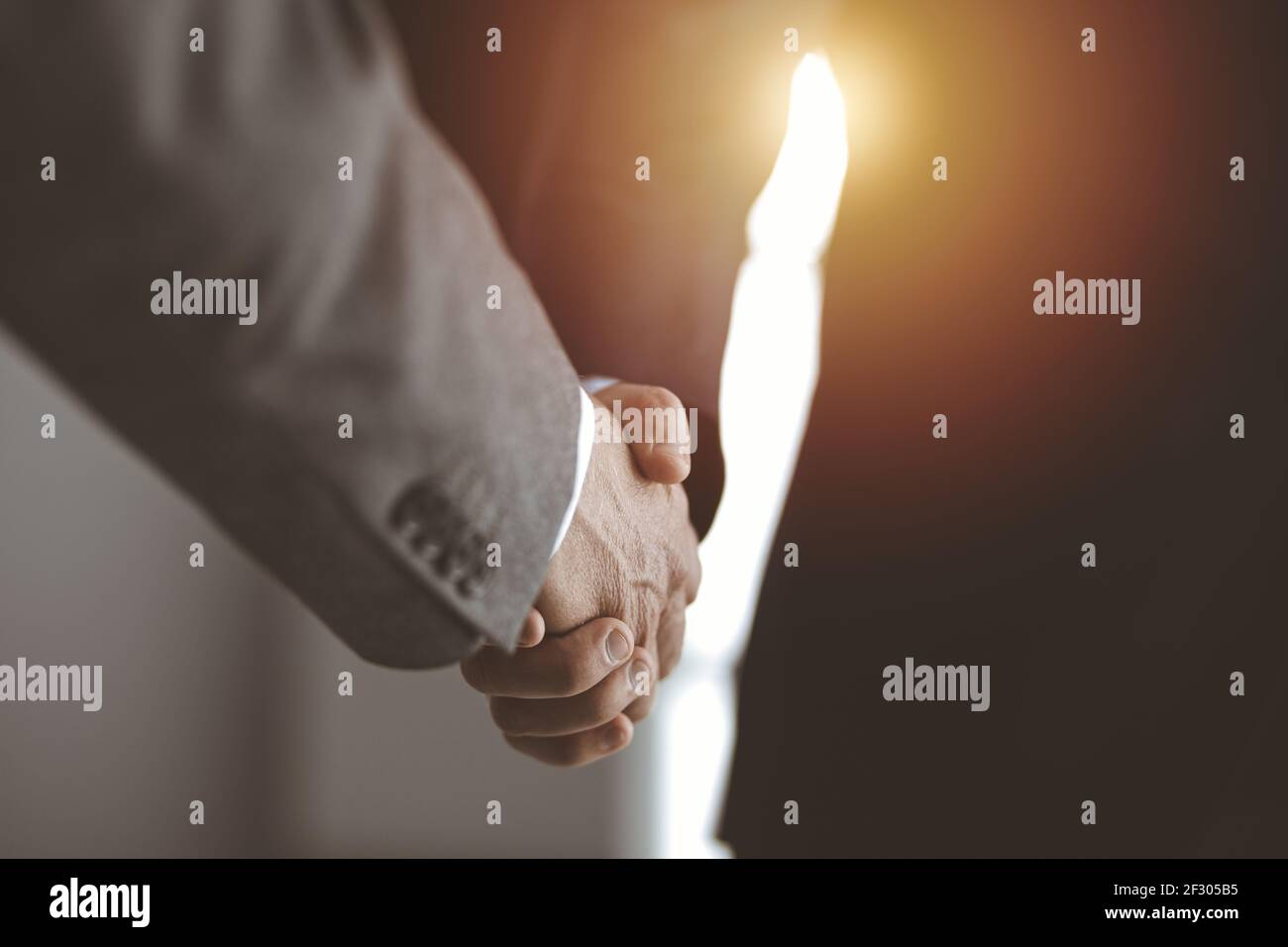 Business people standing and shaking hands in sunny office, close-up ...