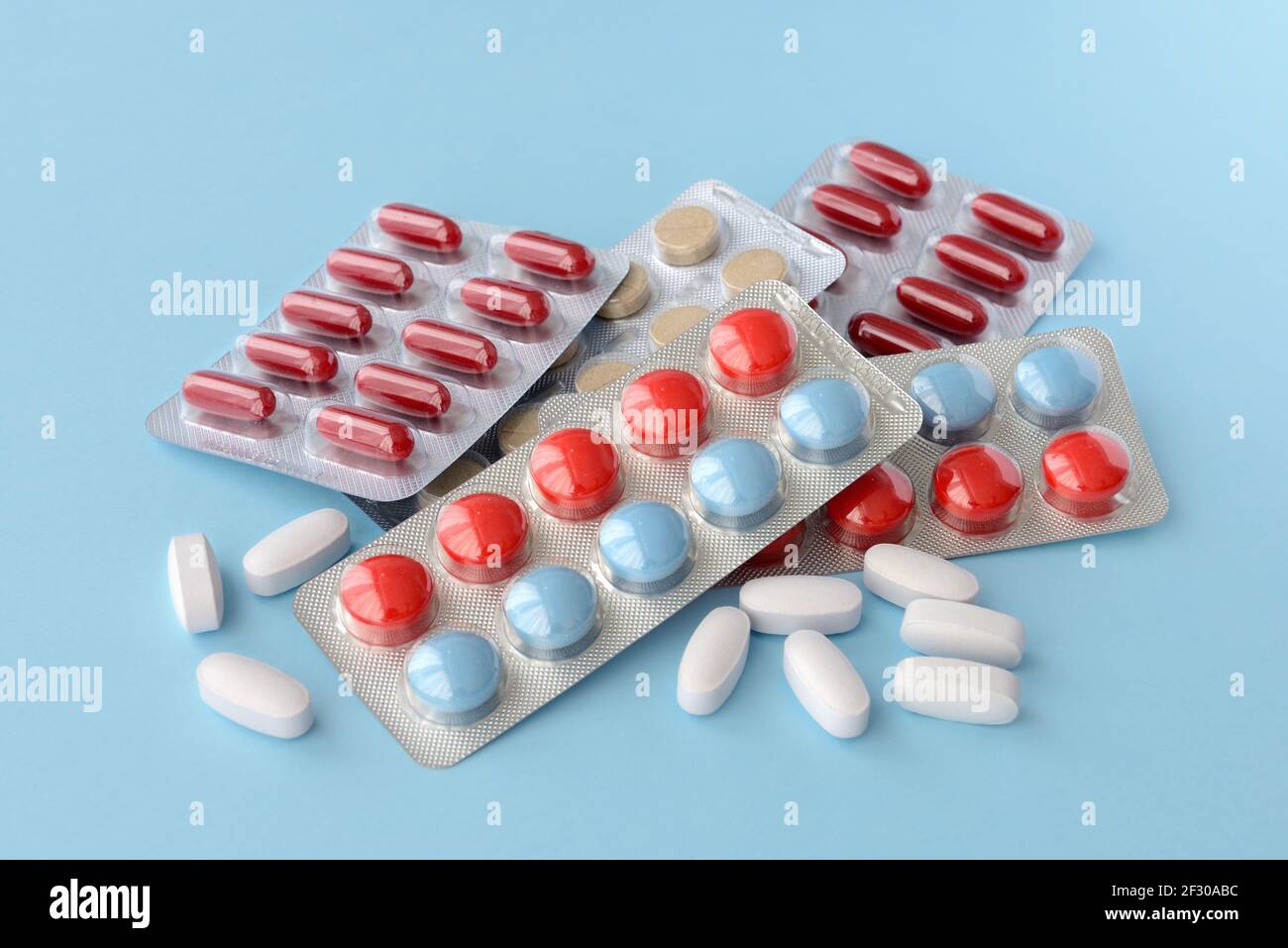 Assorted pharmaceutical medicine pills, tablets and capsules over blue ...