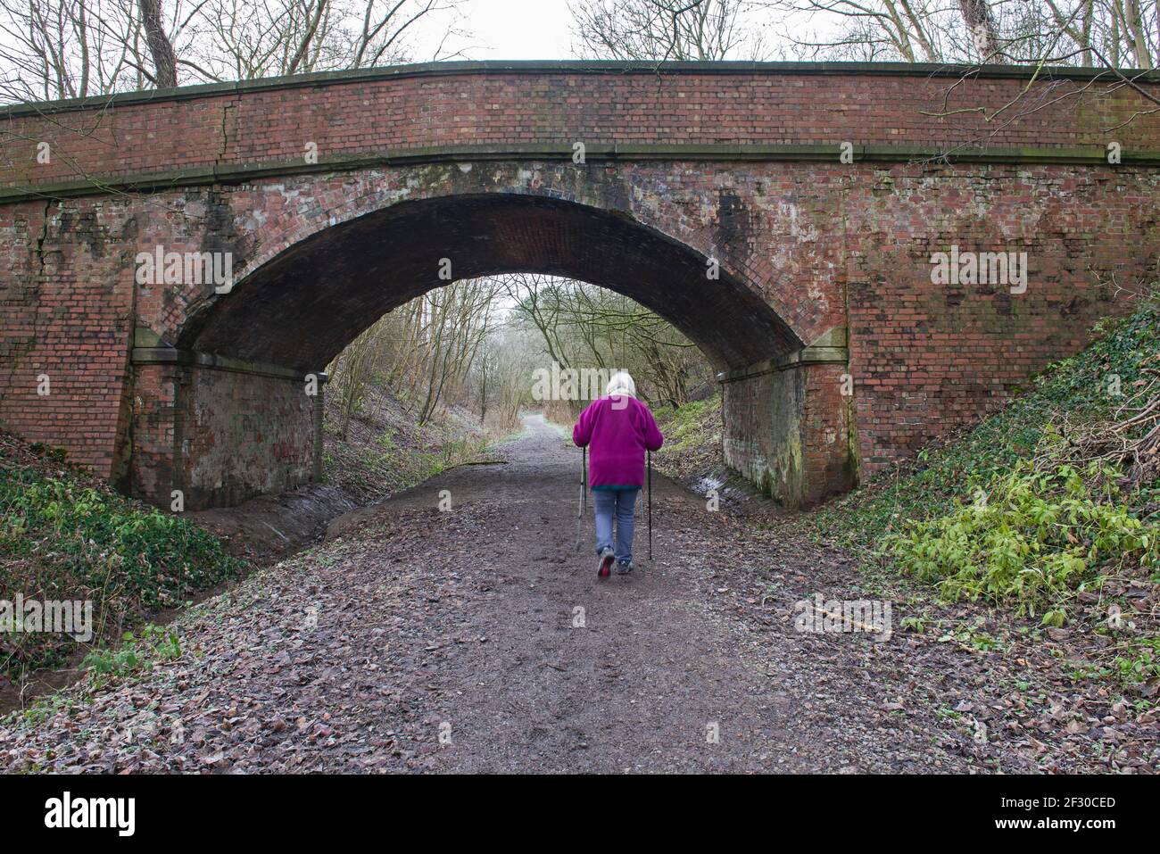 Elderly woman walking along footpath trail through a remote rural ...