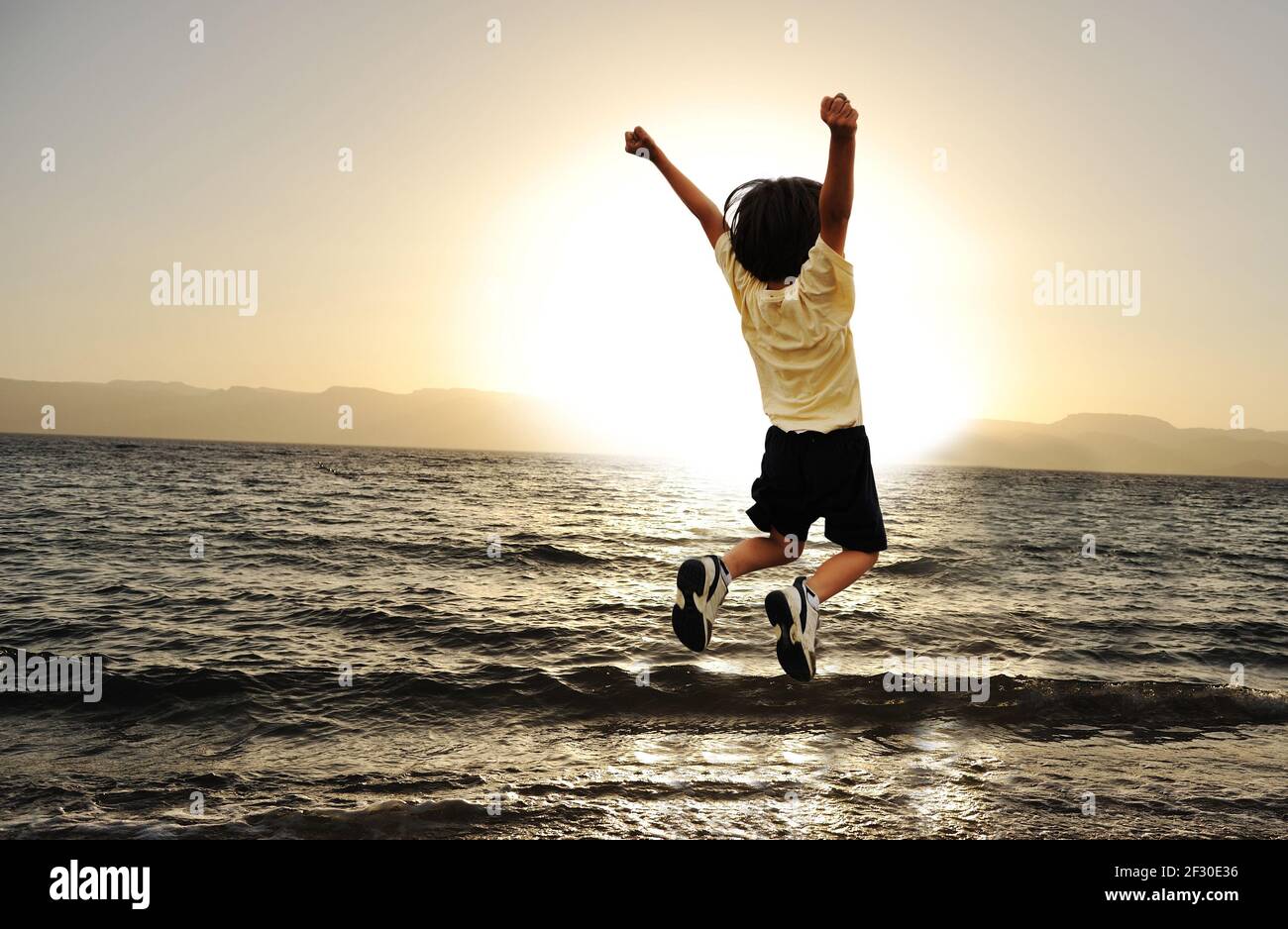 Child jumpin over a sea in sunset Stock Photo - Alamy