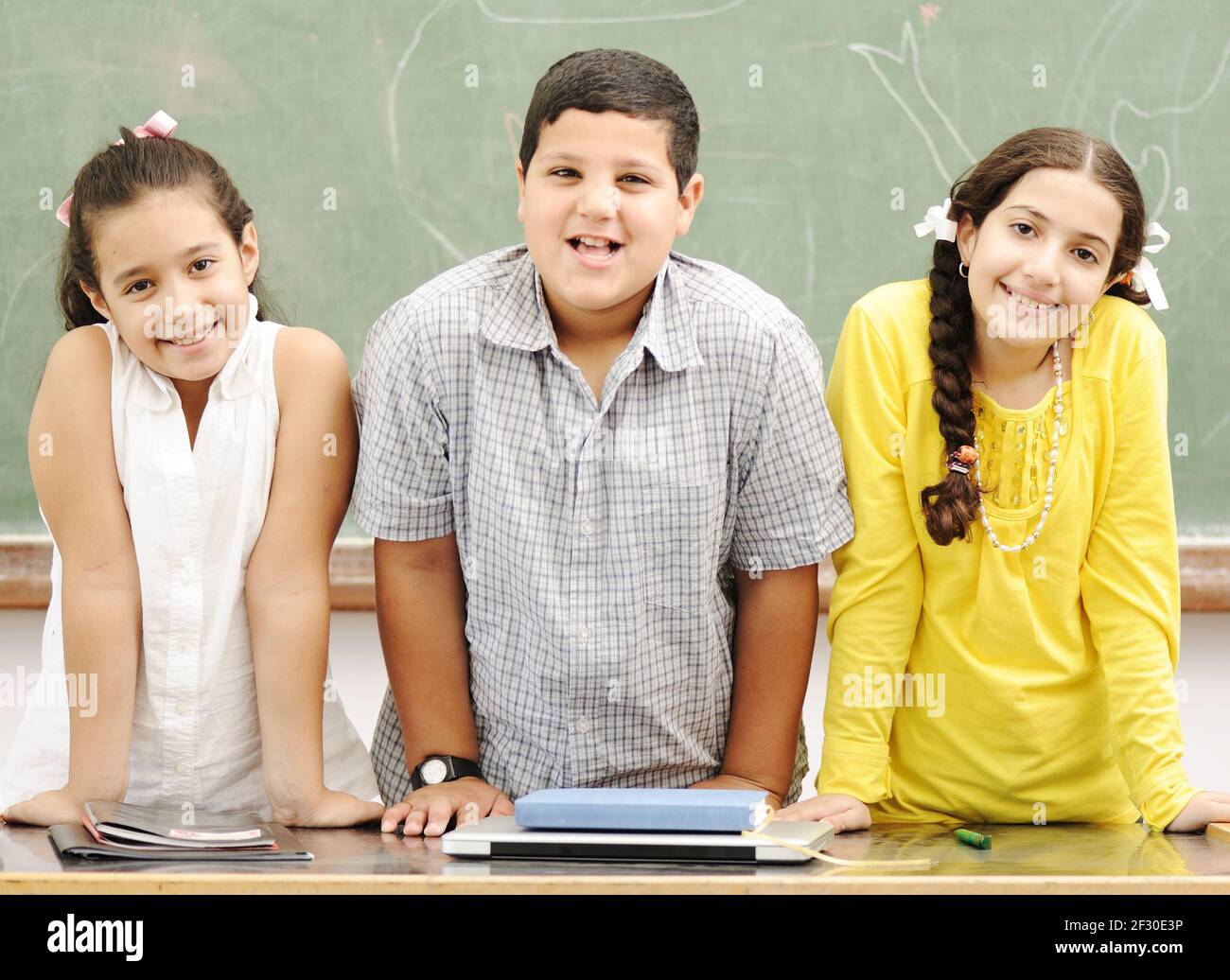 Three happy children standing at board Stock Photo - Alamy