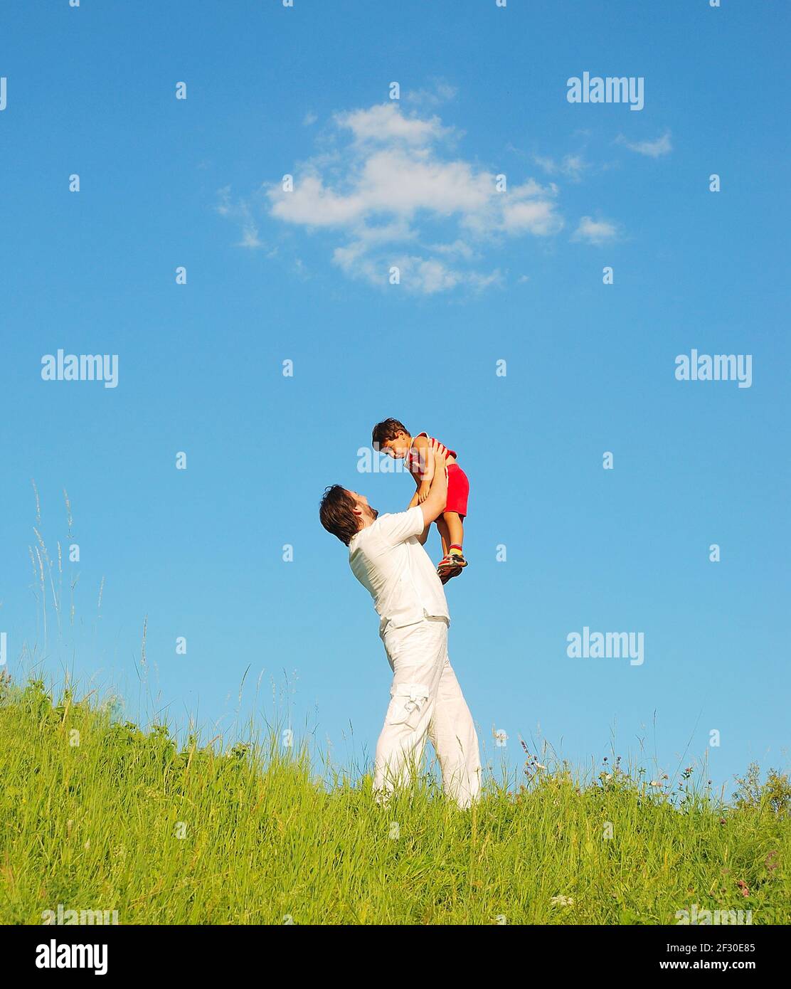 Young father in white with child on beautiful meadow Stock Photo - Alamy