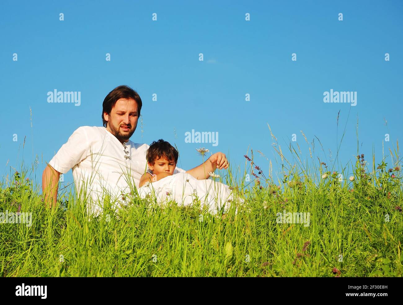 Young father in white with child on beautiful meadow Stock Photo - Alamy
