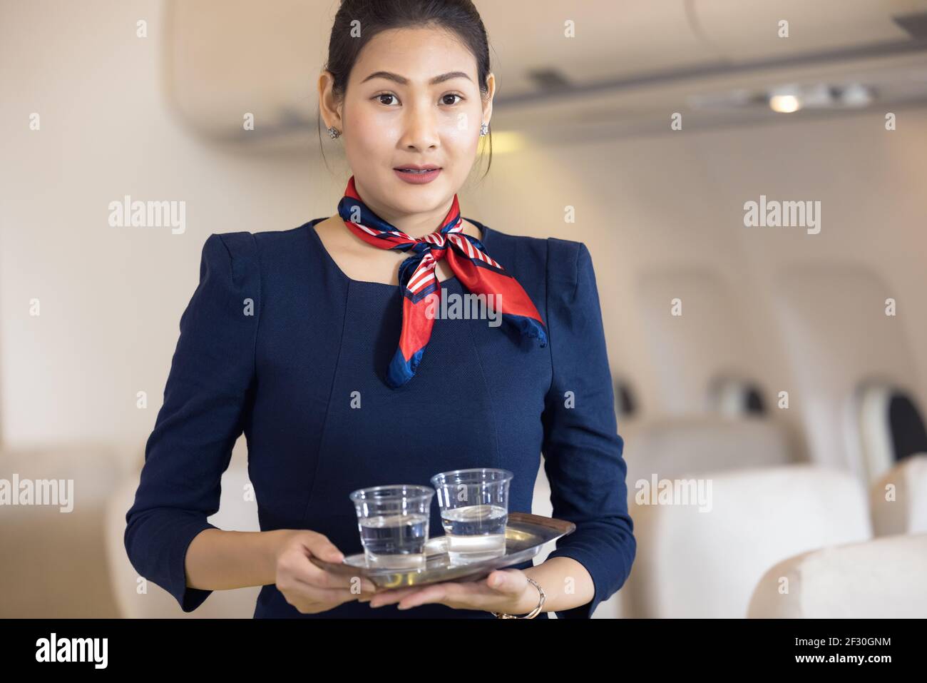 Cabin crew serve water to passenger in airplane . Airline ...