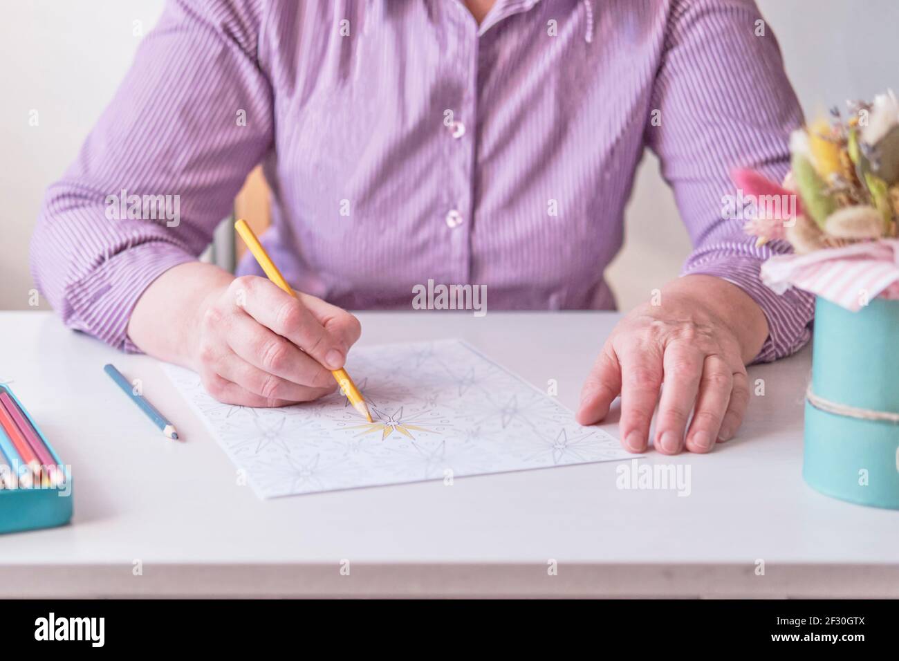 Elderly woman's hand holding a colored pencil. She painting an abstract ...
