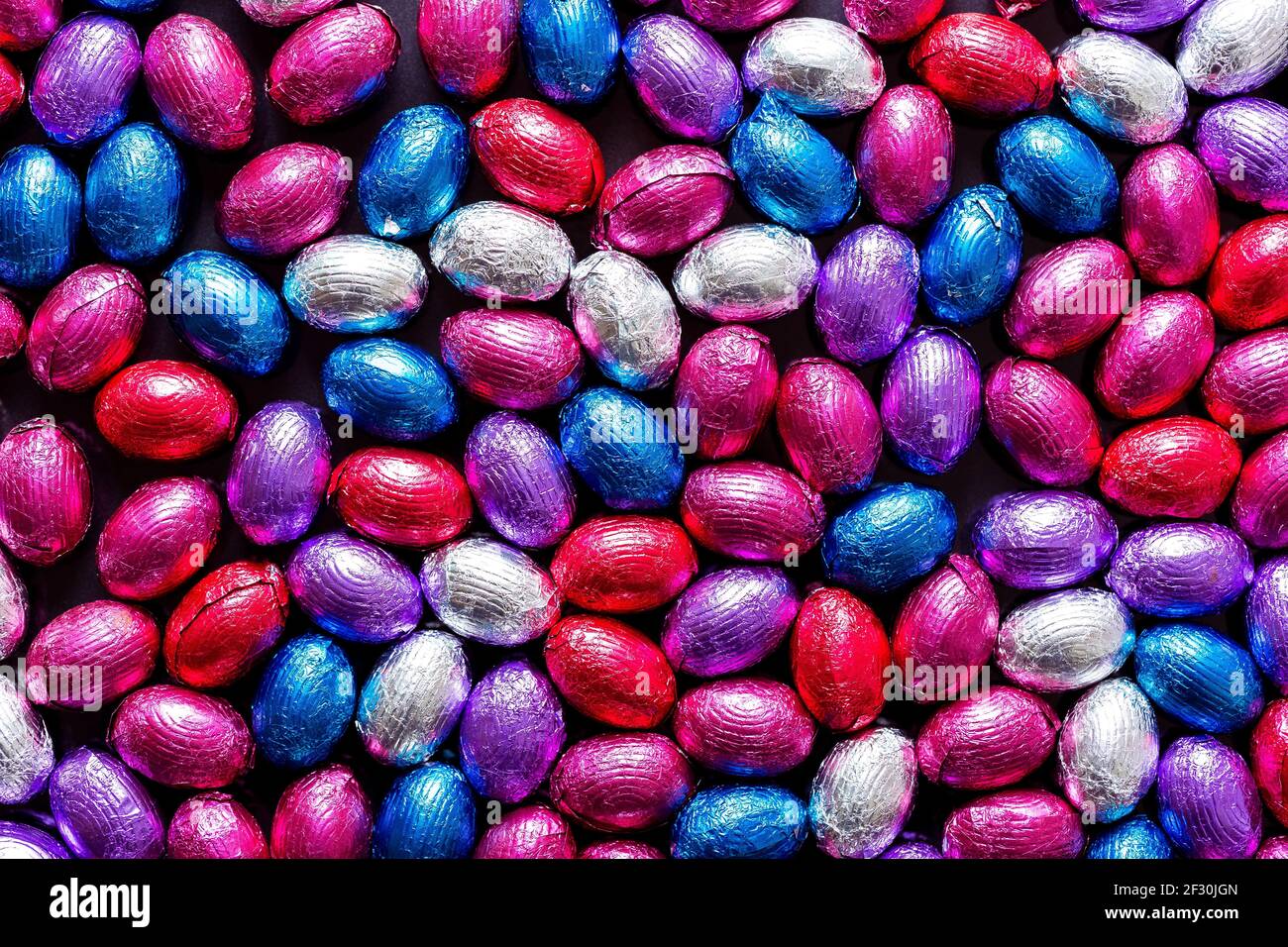 A portrait of a lot of colorful chocolate easter eggs wrapped in ...